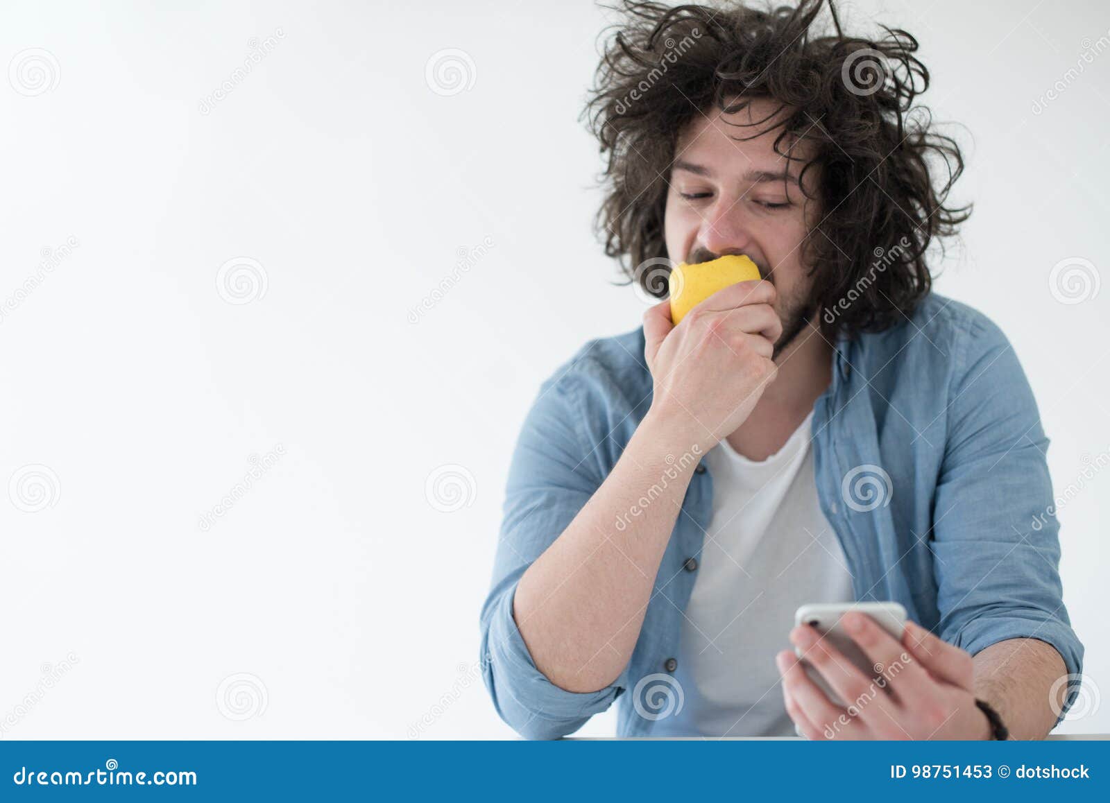 Young Man Eating Apple and Using a Mobile Phone at Home Stock Image ...