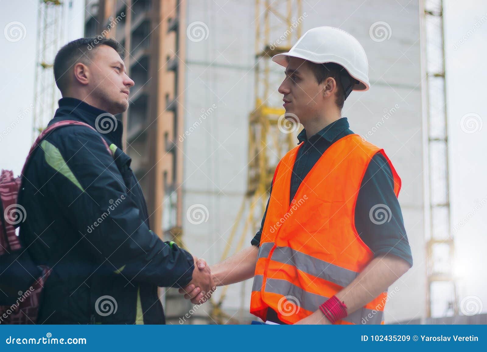 Construction Workers in Protective Helmets and Vests are Shaking Hands ...