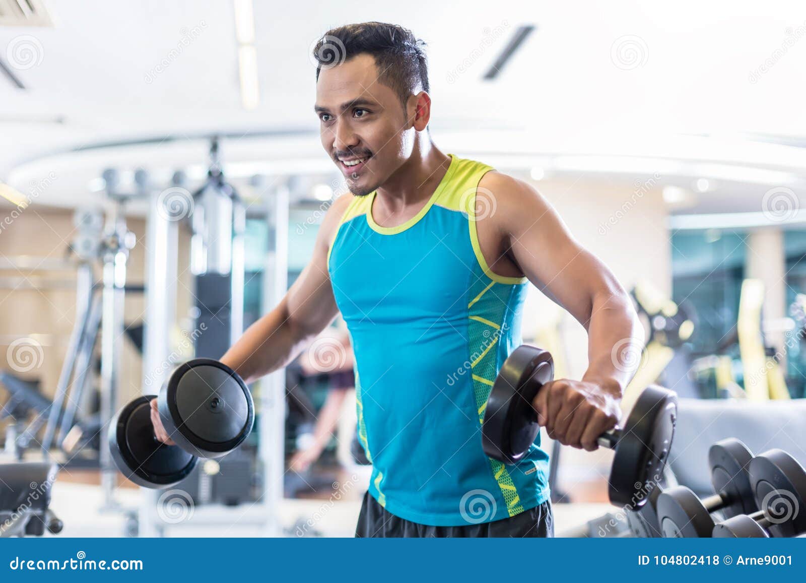 Handsome Determined Young Man Exercising With Dumbbells In A Mod ...
