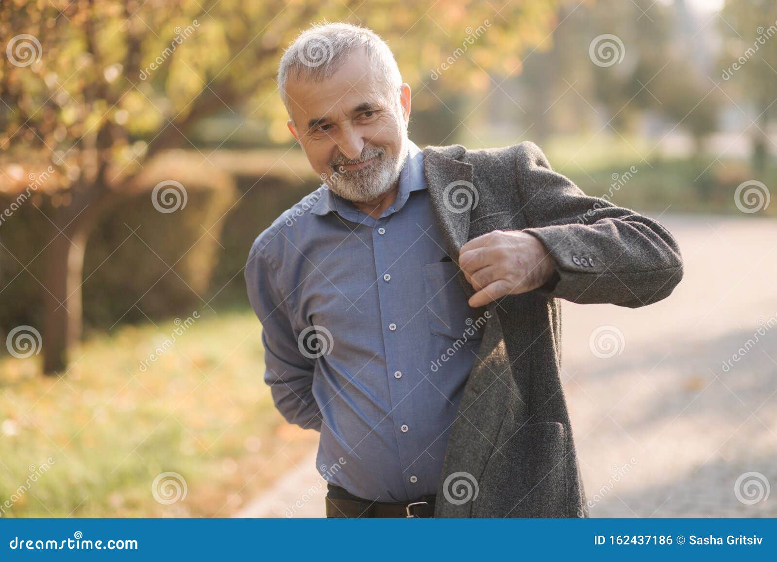 Handsome Elderly Man Putting On A Gray Jacket Old Gray Haired Bearded
