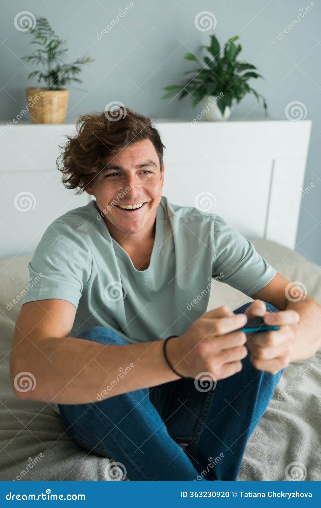 Handsome Excited Gamer Sitting on a Bed and Playing Video Games on a ...