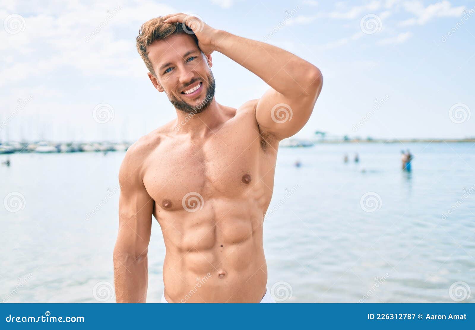 Handsome Fitness Caucasian Man At The Beach On A Sunny Day Showing