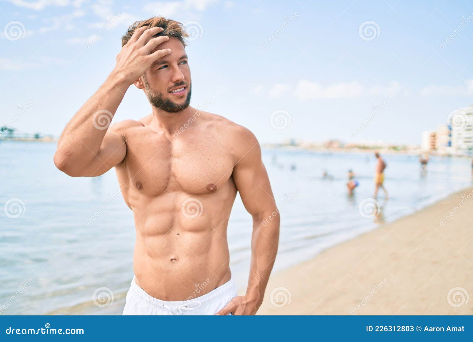 Handsome Fitness Caucasian Man At The Beach On A Sunny Day Showing