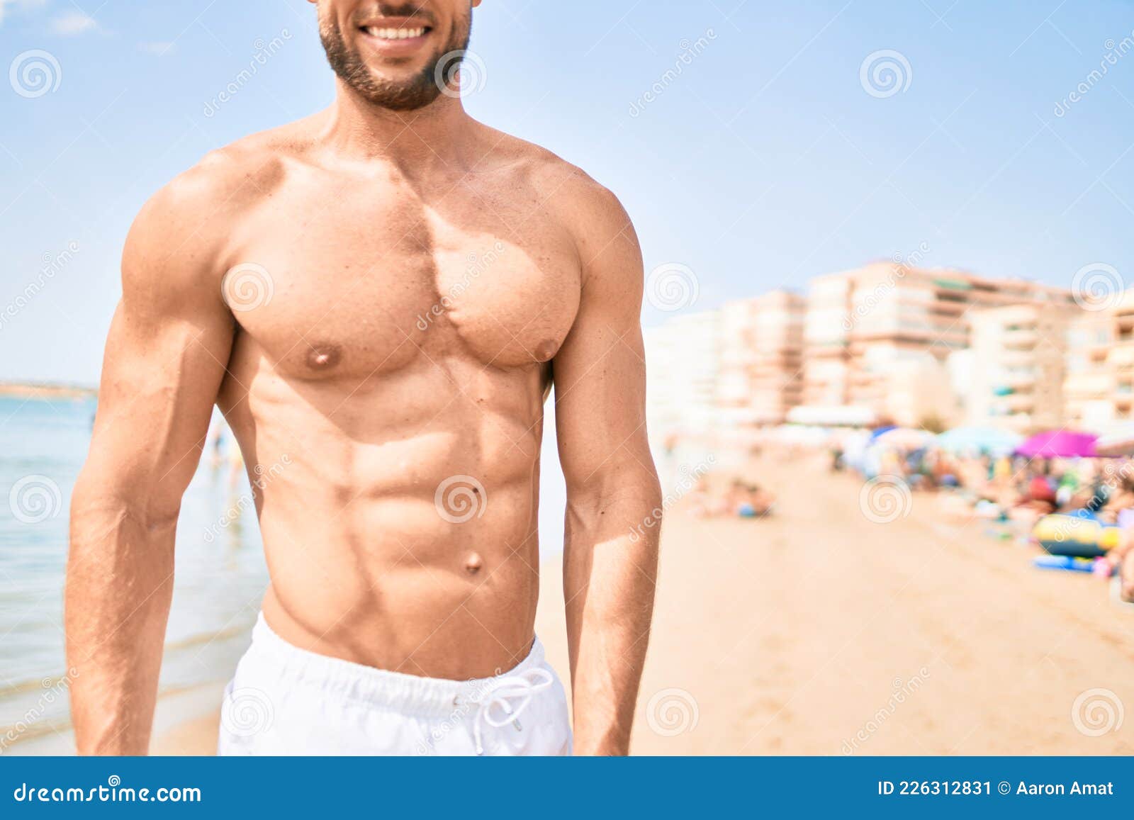 Handsome Fitness Caucasian Man At The Beach On A Sunny Day Showing