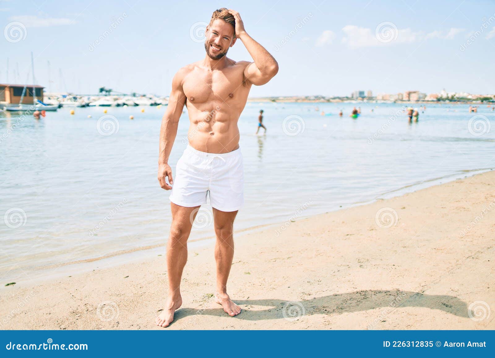 Handsome Fitness Caucasian Man At The Beach On A Sunny Day Showing