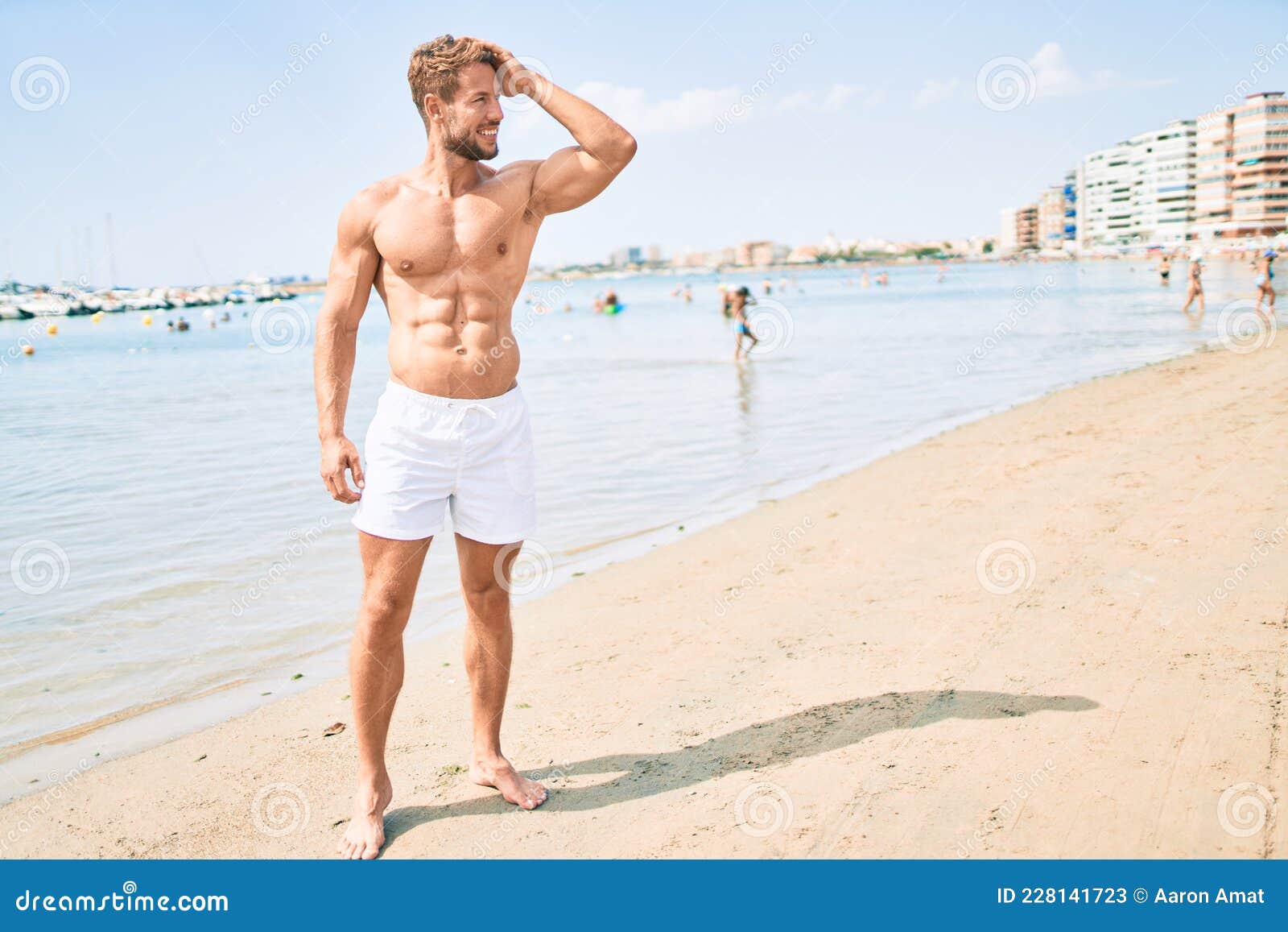 Handsome Fitness Caucasian Man At The Beach On A Sunny Day Showing
