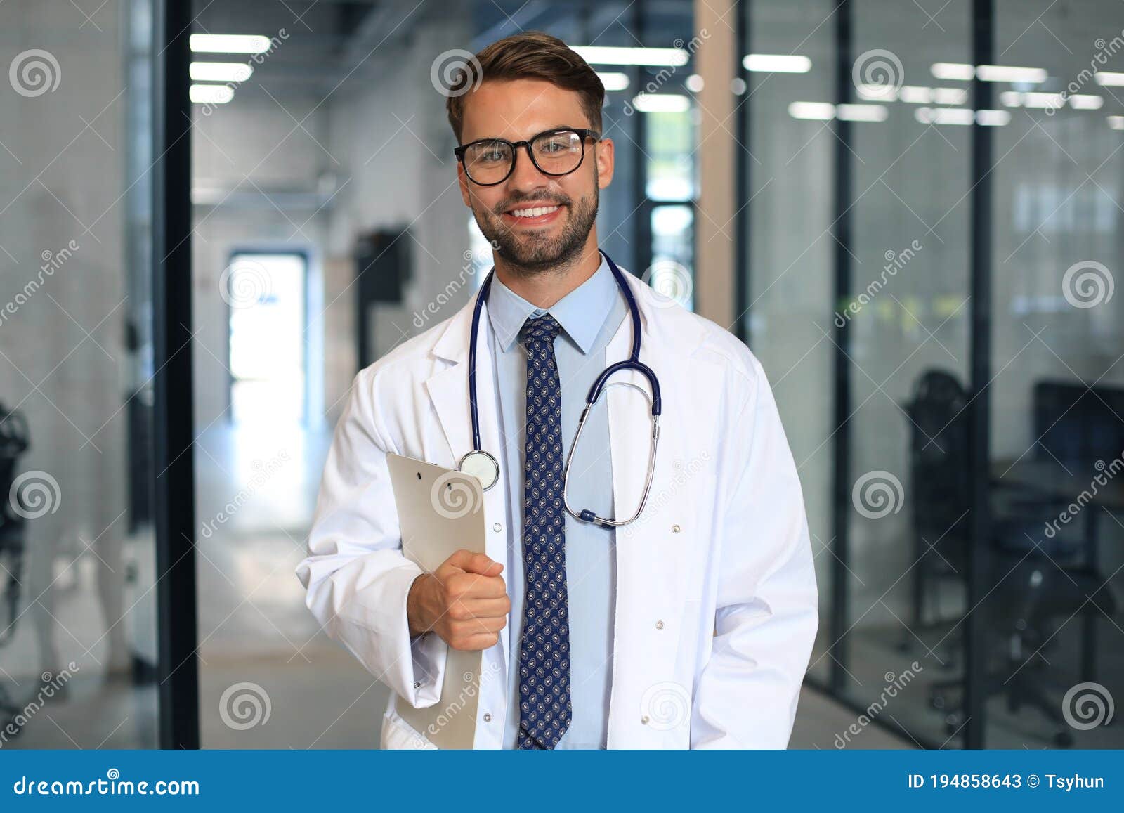 Handsome Friendly Young Doctor on Hospital Corridor Looking at Camera ...
