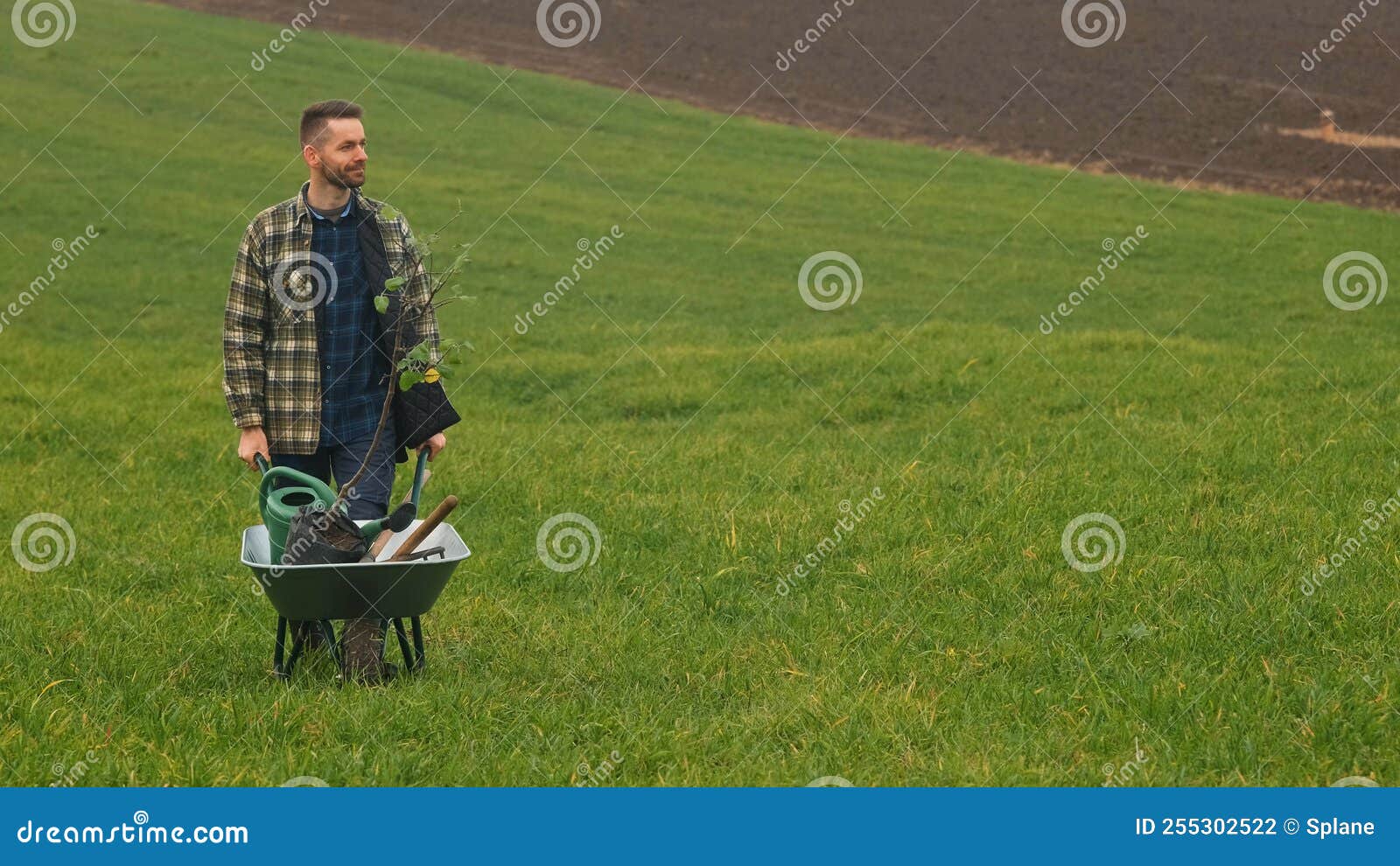 The Handsome Gardener Walking with a Wheelbarrow through the Field ...