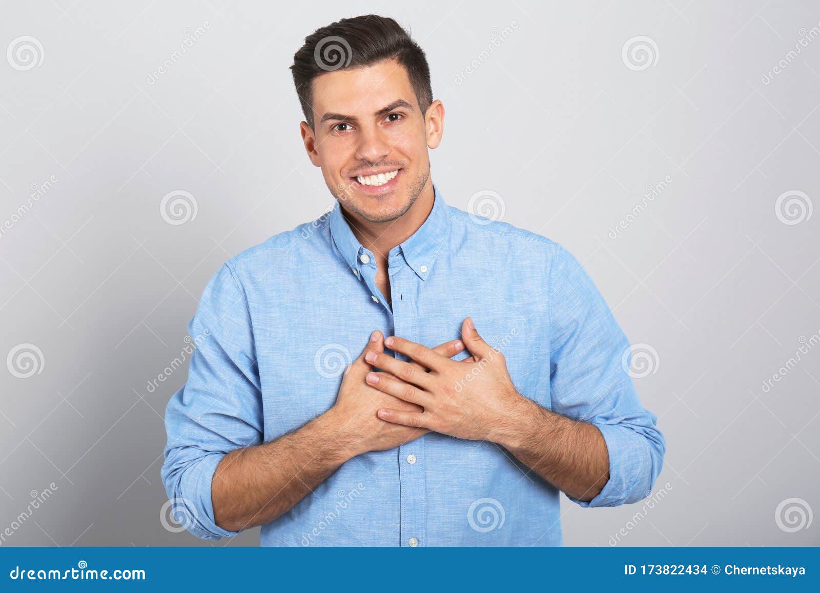 Handsome Grateful Man with Hands on Chest Against Light Grey Background ...