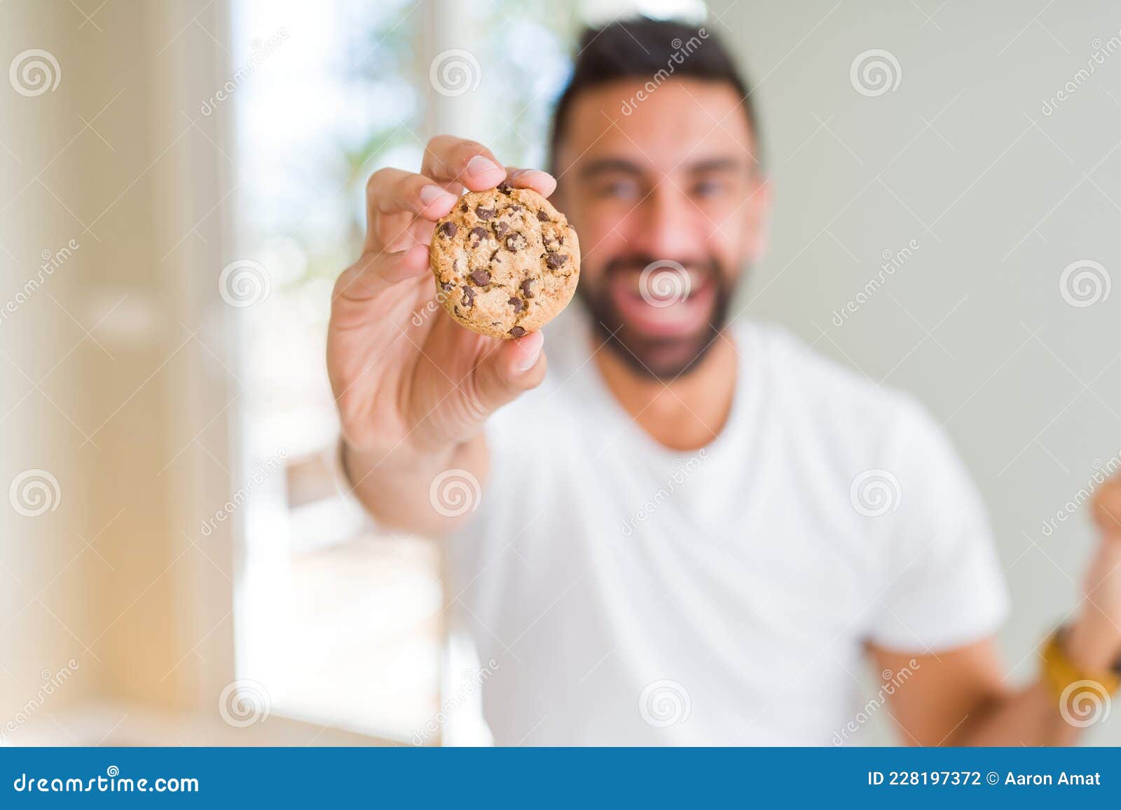Handsome Hispanic Man Eating Chocolate Chips Cookies Screaming Proud