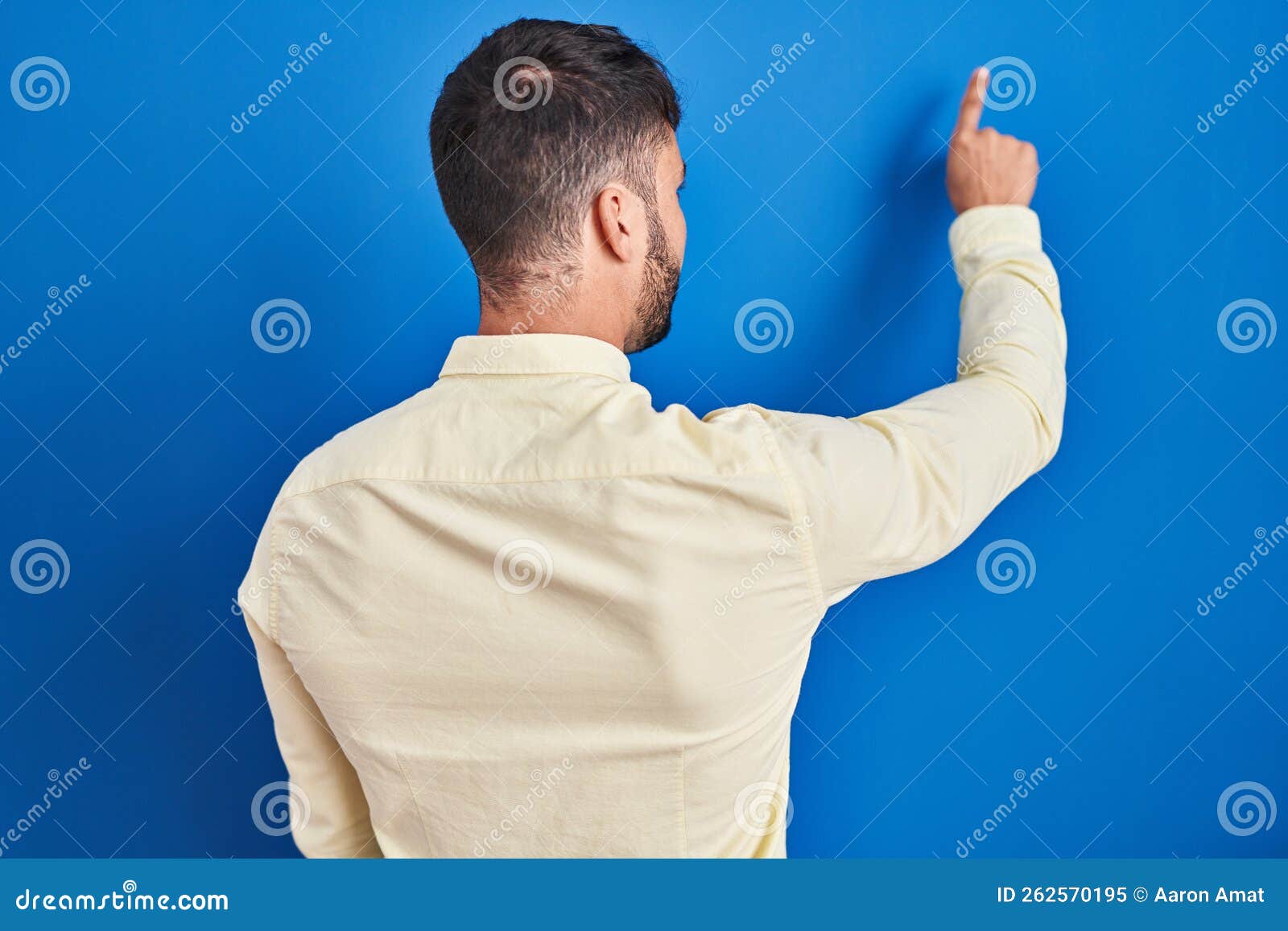 Handsome Hispanic Man Standing Over Blue Background Posing Backwards ...