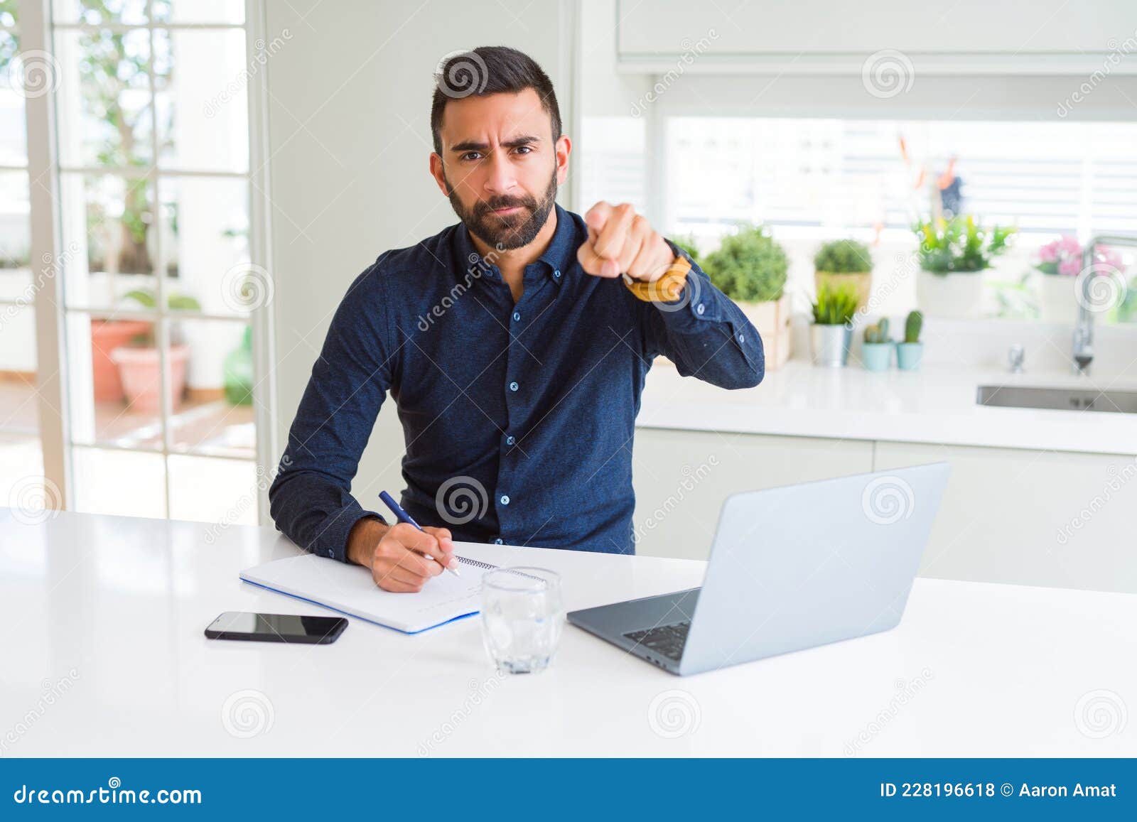 Handsome Hispanic Man Working Using Computer and Writing on a Paper ...