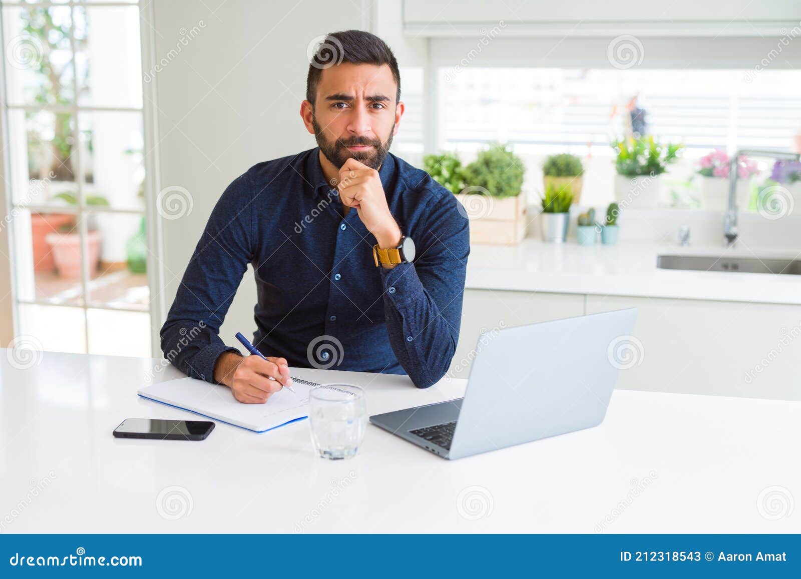 Handsome Hispanic Man Working Using Computer and Writing on a Paper ...