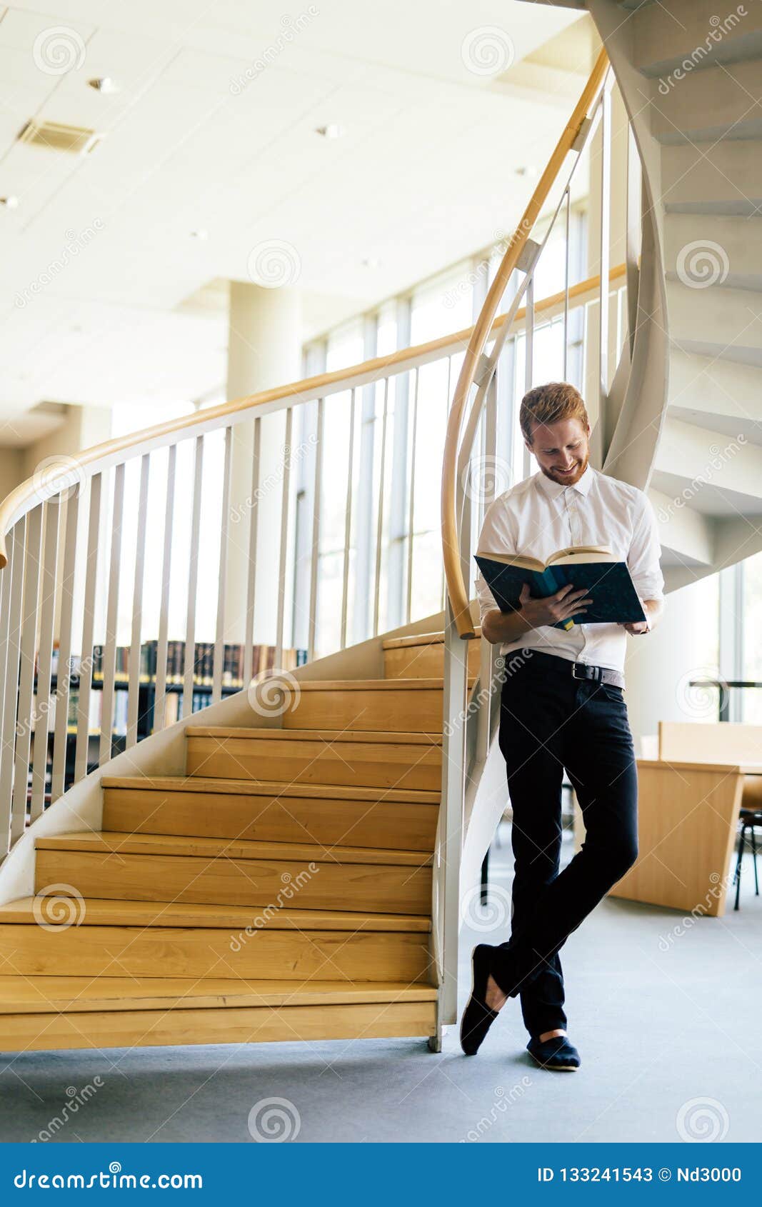 Handsome Intelligent Guy Reading a Book in a Library Stock Image ...