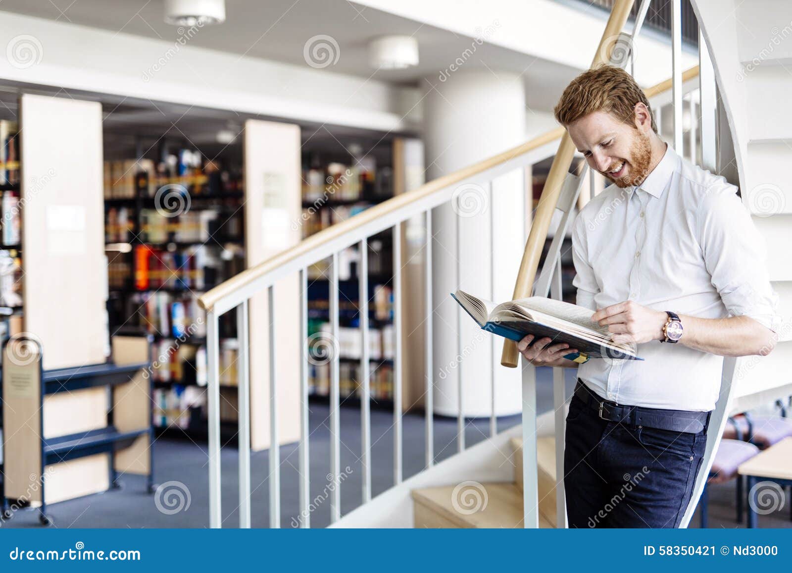 Handsome Intelligent Guy Reading a Book in a Library Stock Image ...