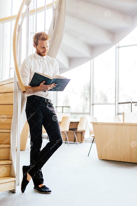 Handsome Intelligent Guy Reading a Book in a Library Stock Image ...
