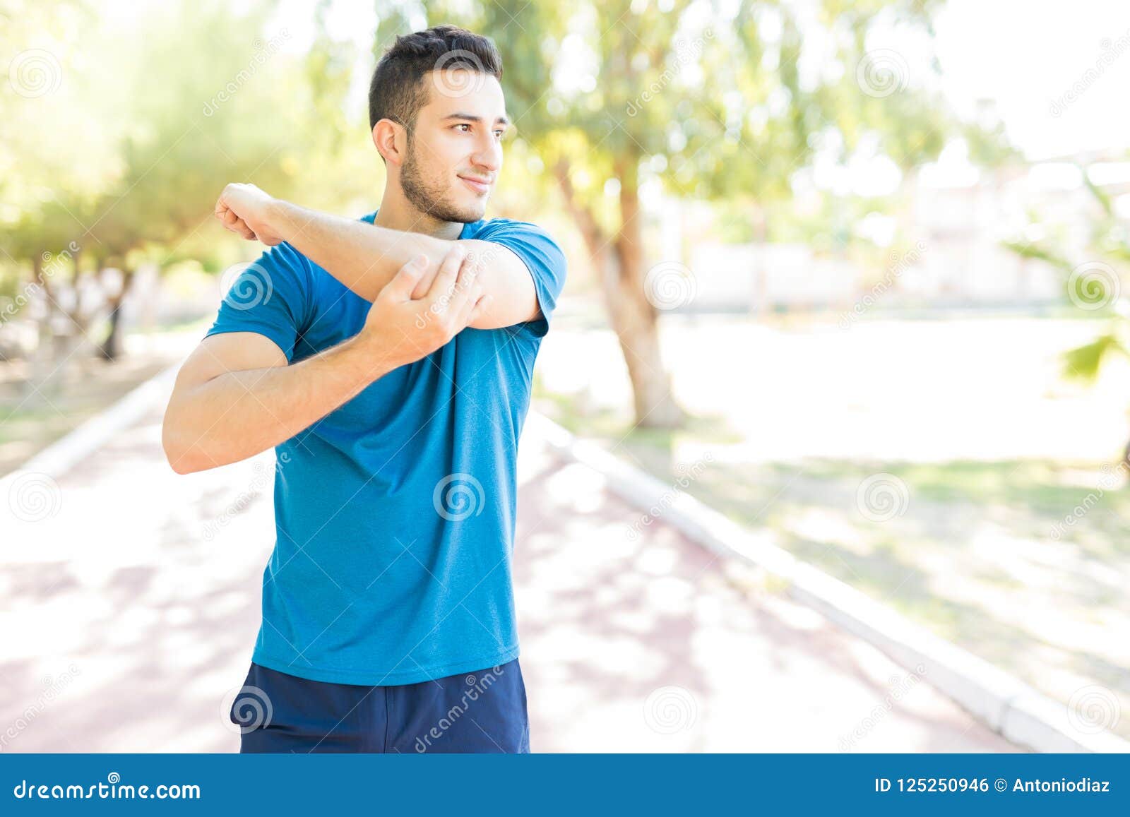 Male Runner Stretching Arm before Workout in Park Stock Photo - Image ...