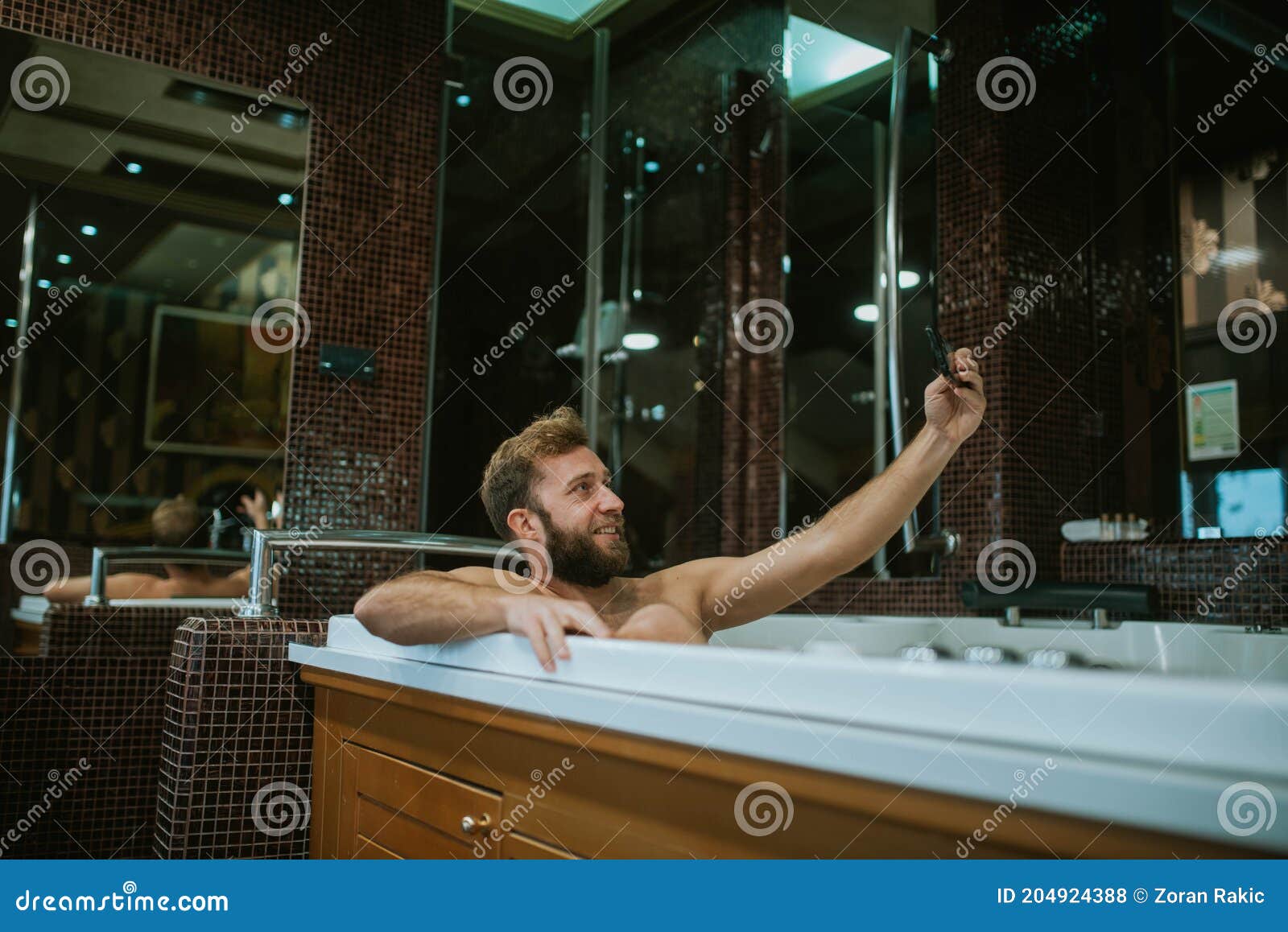 A Handsome Man with a Beard, Sitting in a Spa and Taking a Selfie Stock ...