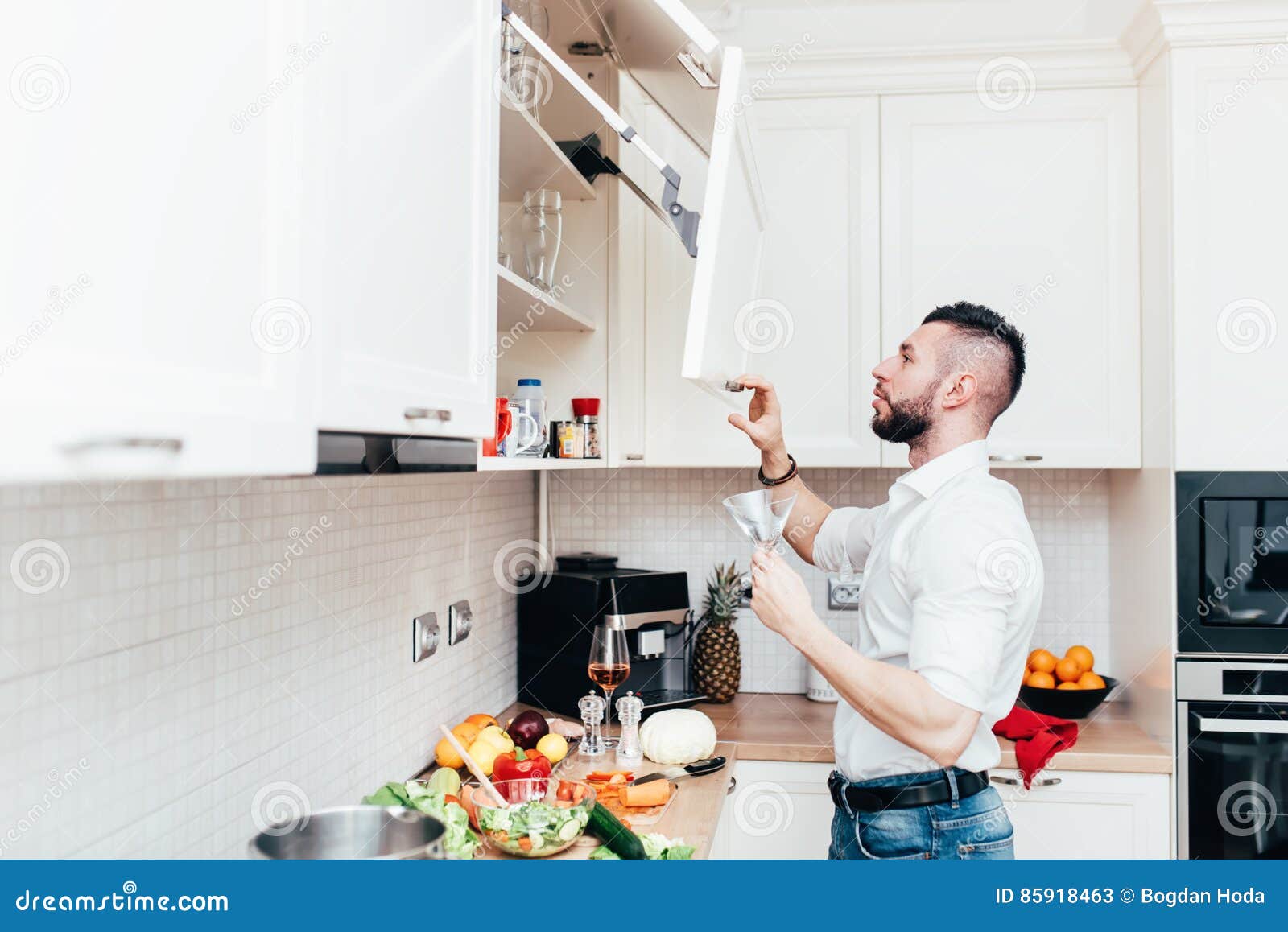 Handsome Man Cooking and Drinking in New Kitchen, Preparing Glasses ...