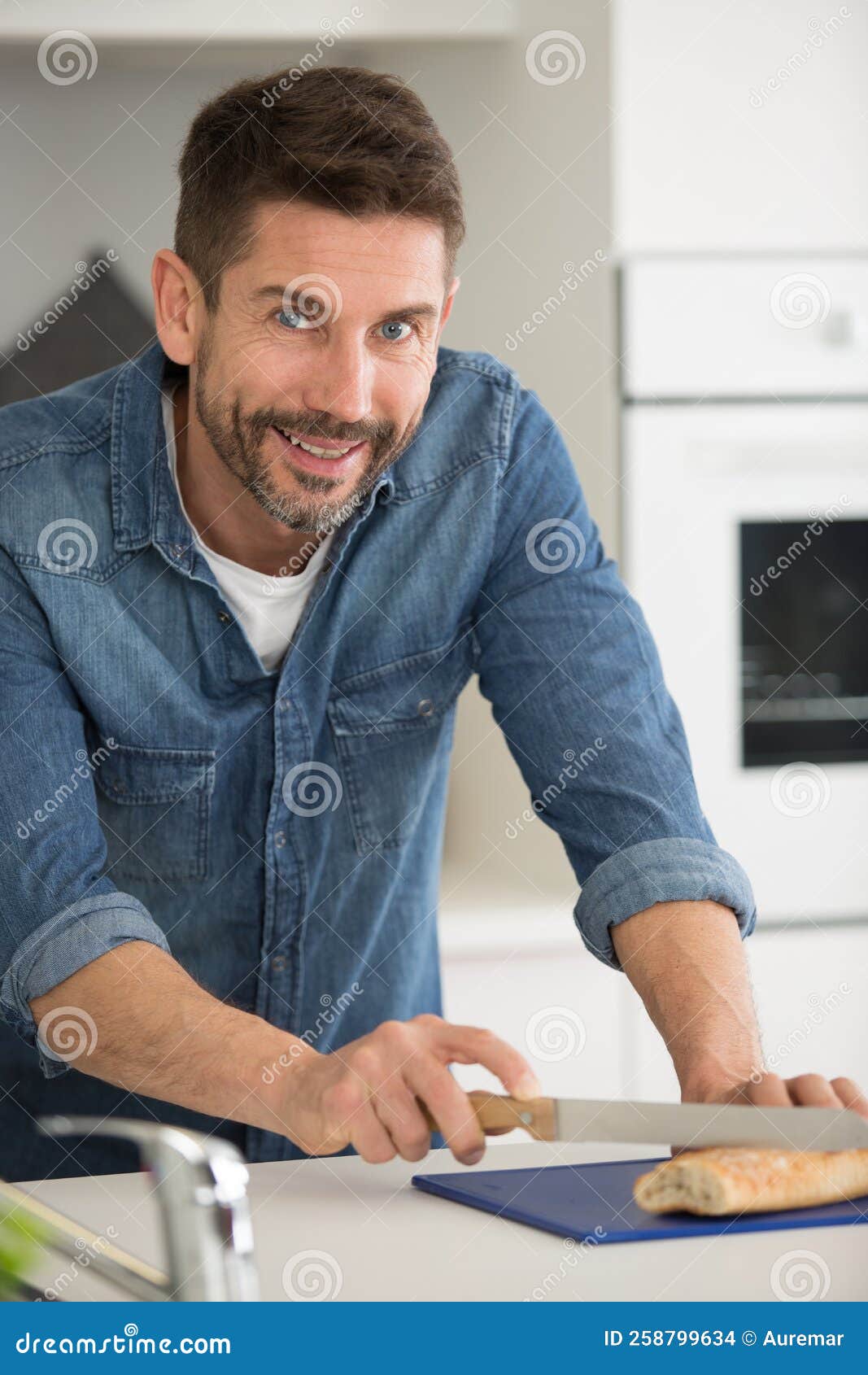Handsome Man Cutting Bread and Smiling Stock Photo - Image of beard, kitchen: 258799634