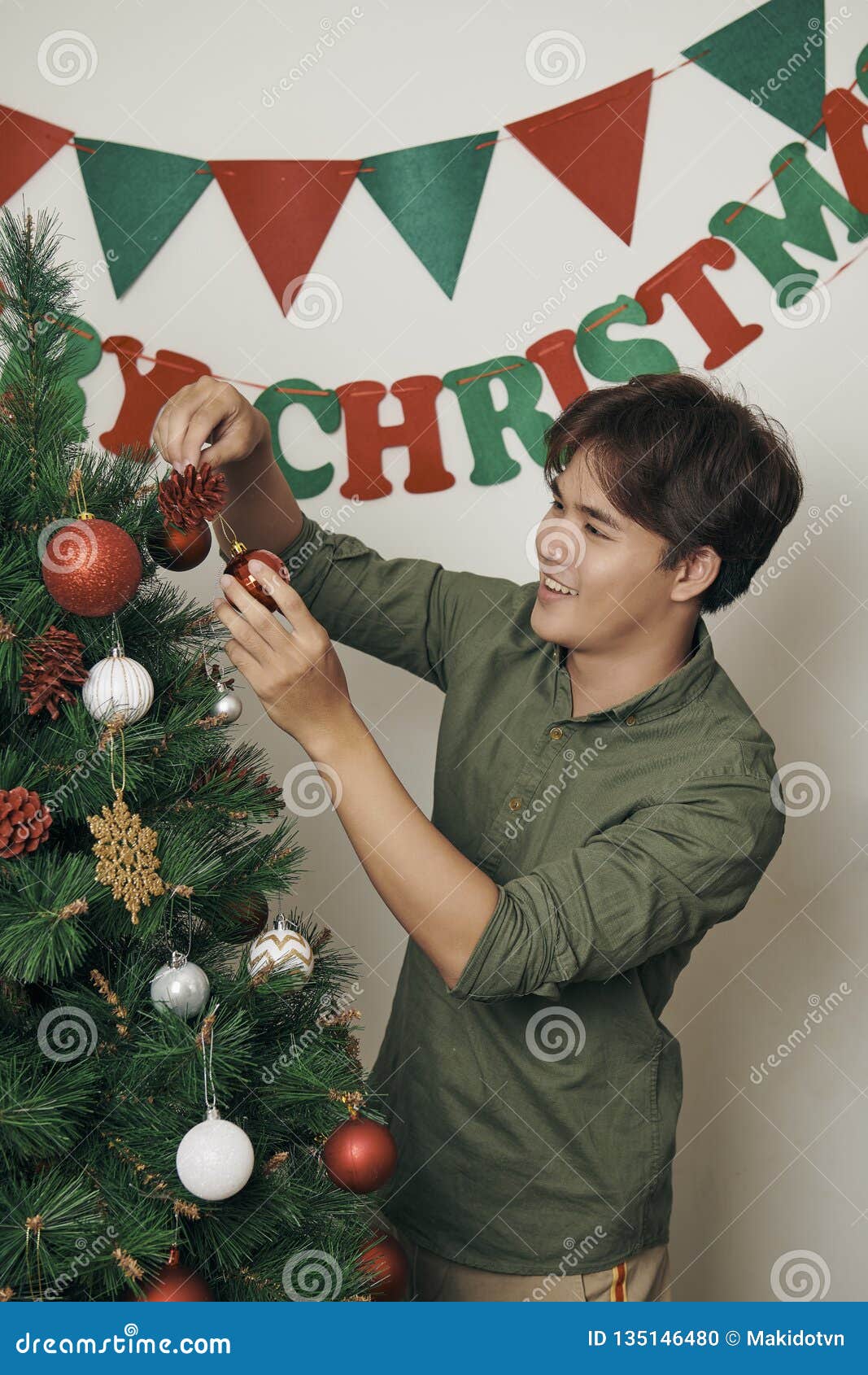 Handsome Man Decorating Christmas Tree with Baubles and Looking at ...