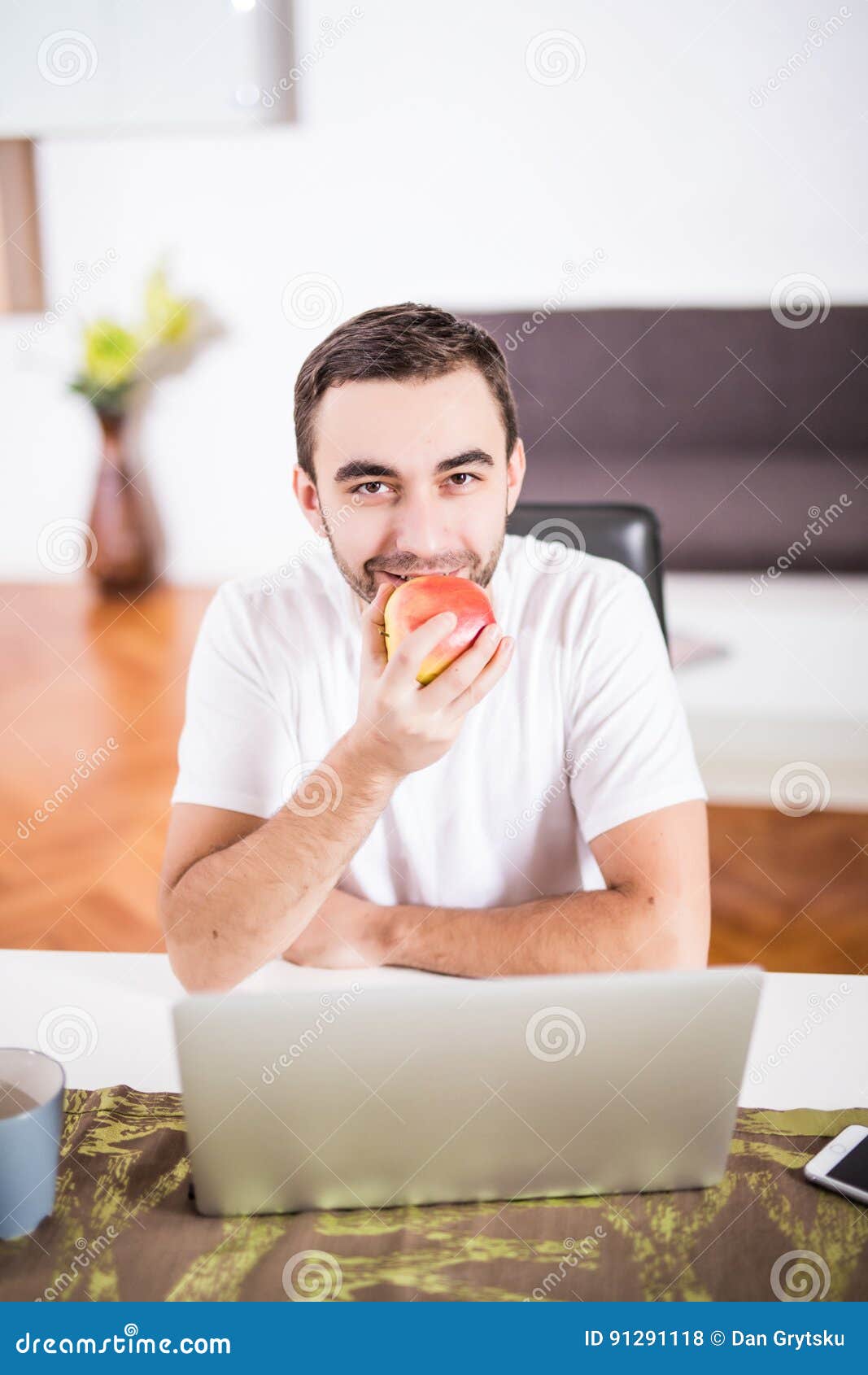 Handsome Man Eating Apple and Working with Laptop at Kitchen at Home ...