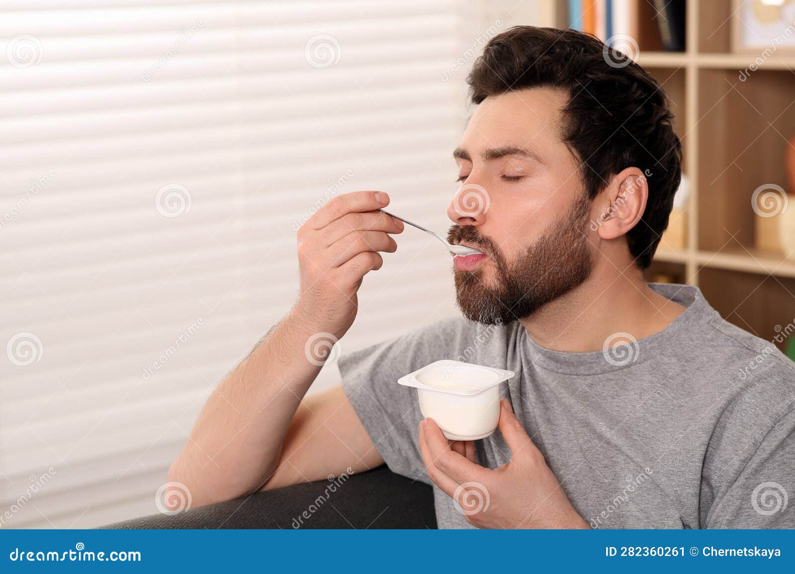 Handsome Man Eating Delicious Yogurt at Home. Space for Text Stock ...