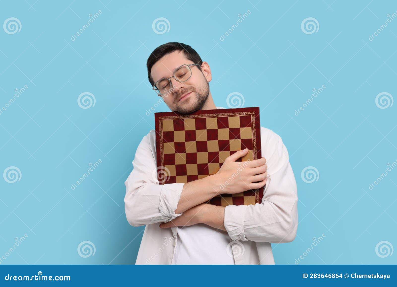Handsome Man Holding Chessboard on Light Blue Background Stock Photo ...