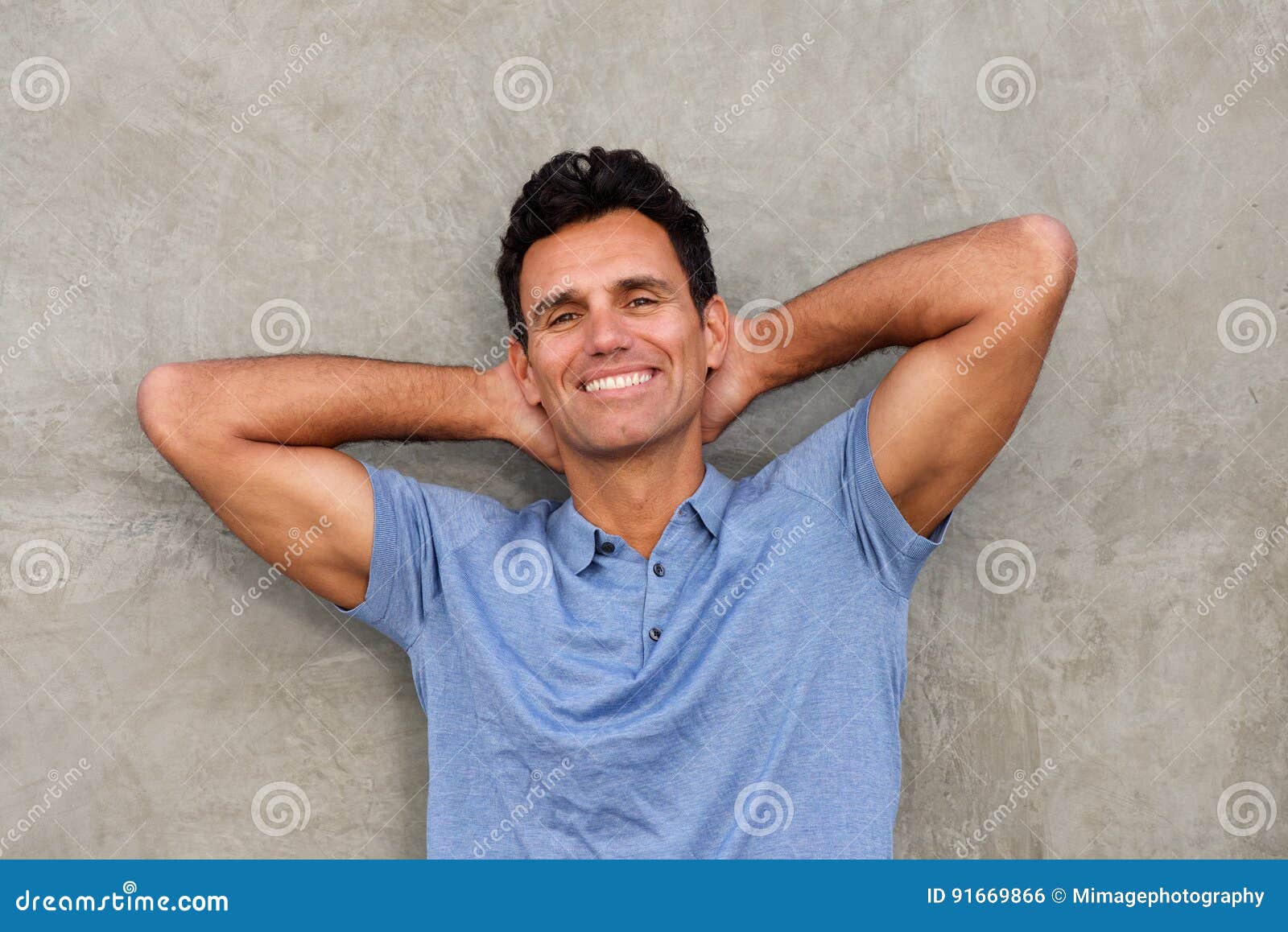 Handsome Man Leaning Against Wall with Hands Behind Head Stock Photo ...