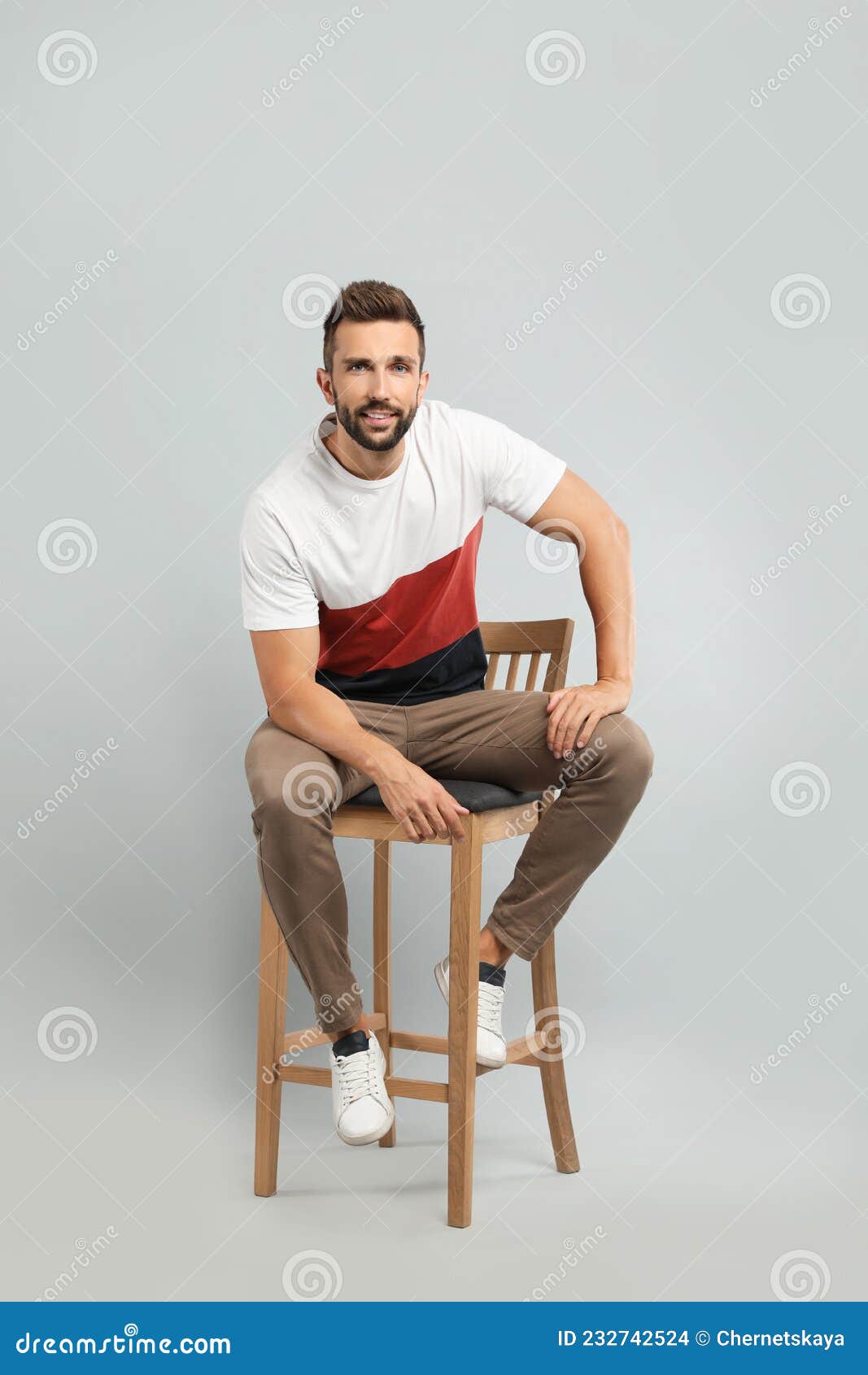 Handsome Man Sitting on Stool Against Light Grey Background Stock Photo ...