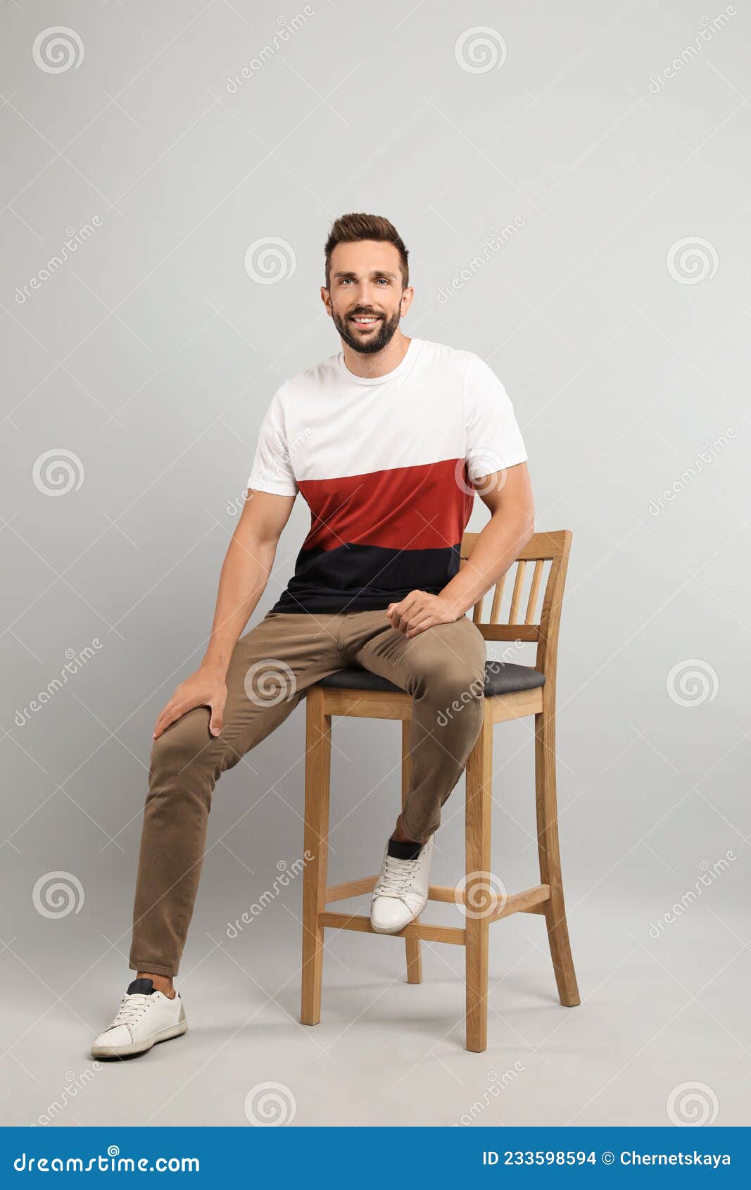 Handsome Man Sitting on Stool Against Light Grey Background Stock Photo ...