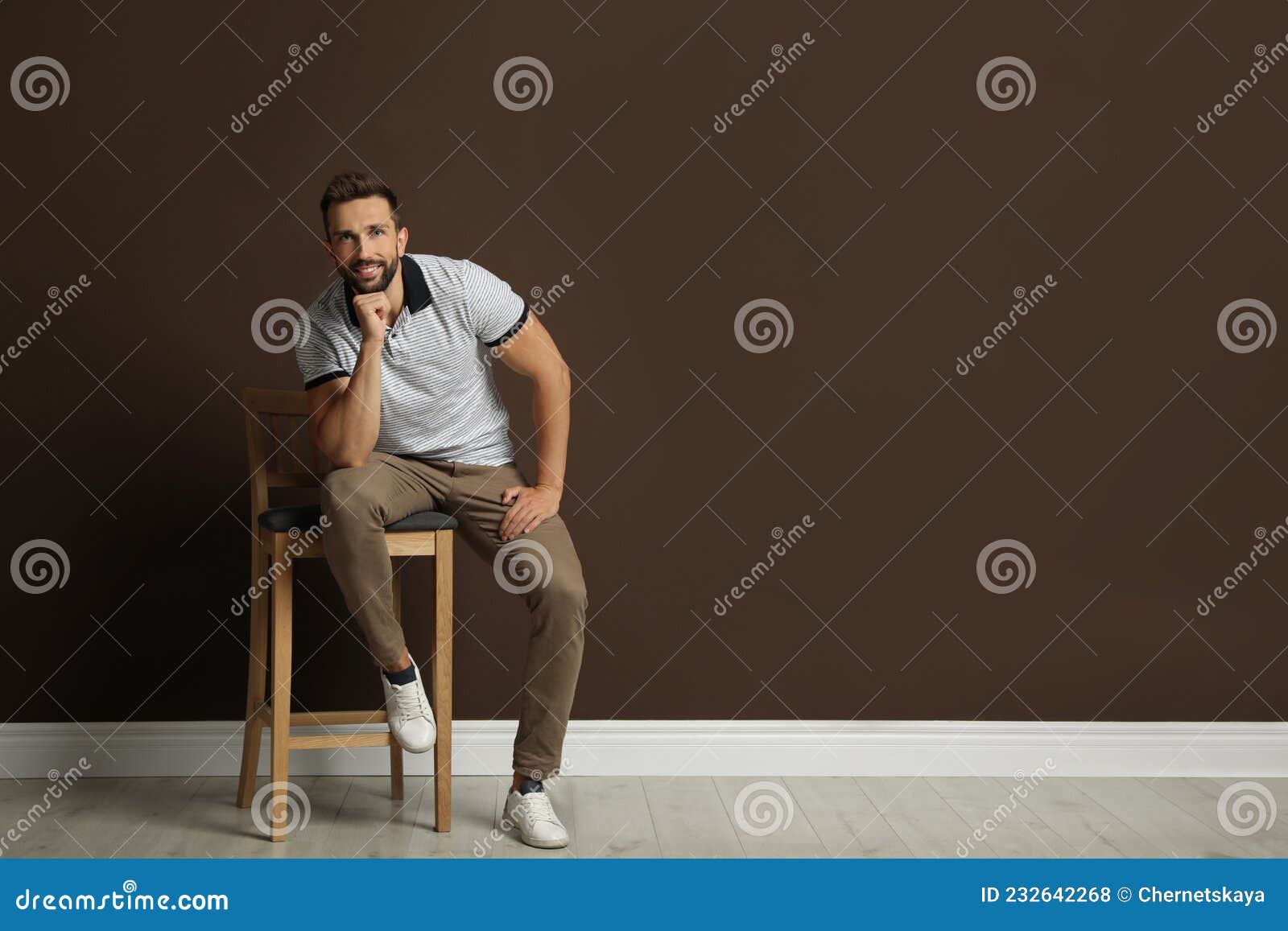 Handsome Man Sitting on Stool Near Brown Wall. Space for Text Stock ...