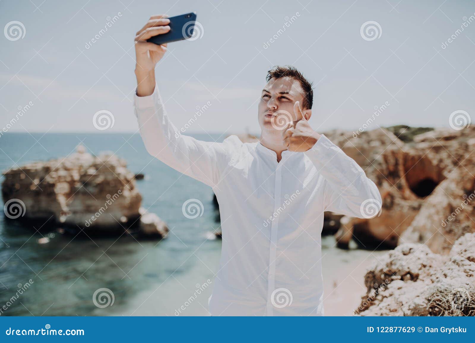 Handsome Man Taking A Selfie With Thumbs Up At Cliff Ocean Beach Stock