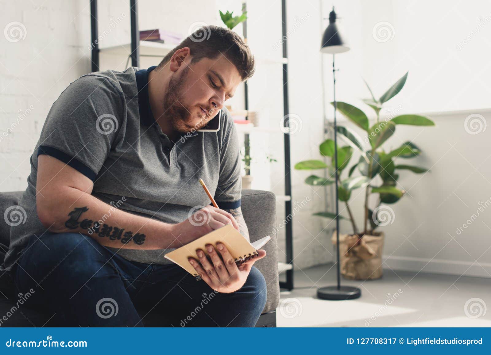 Handsome Overweight Man Writing Something To Notebook on Sofa Stock ...