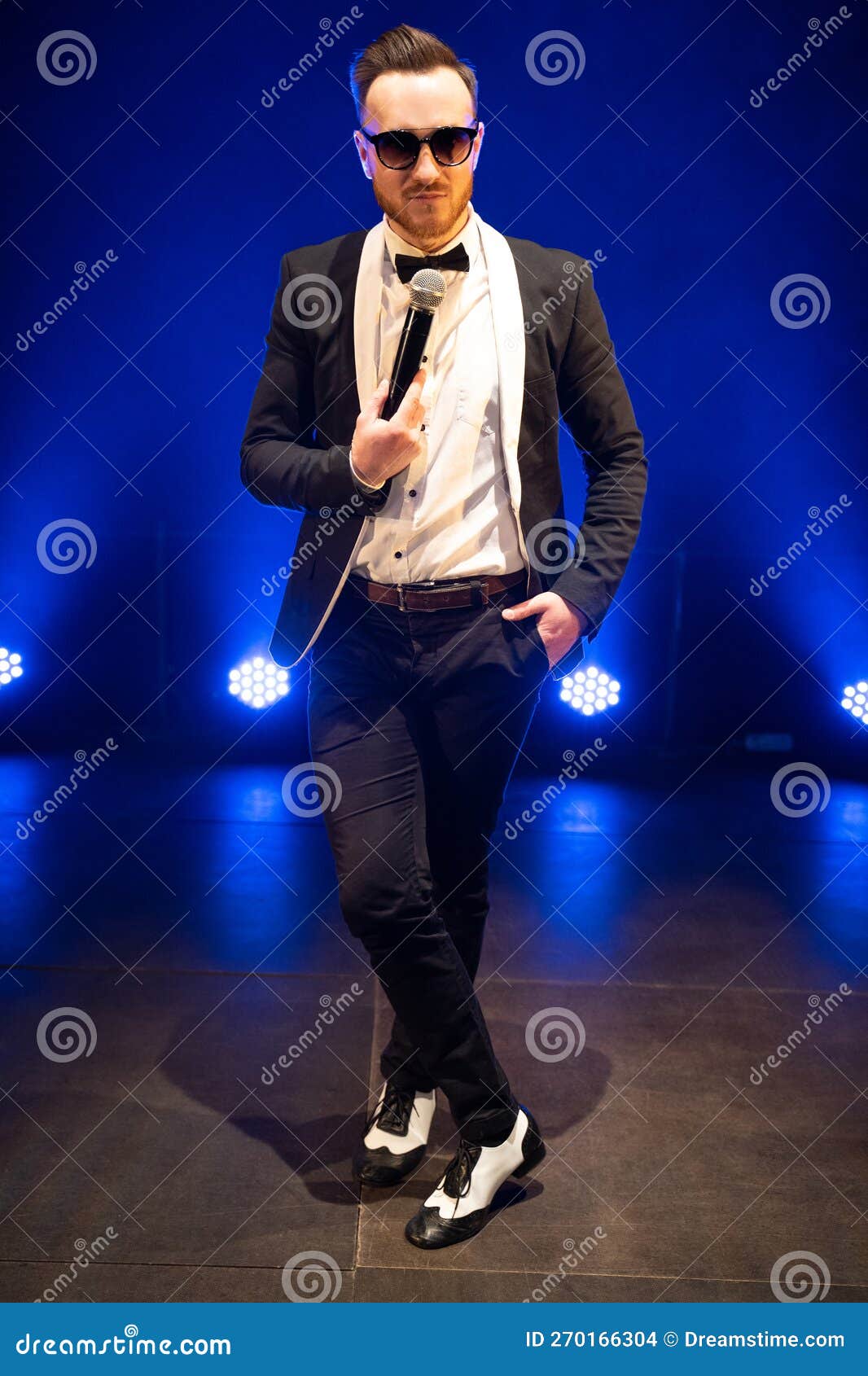 Handsome Presenter and Showman in a Stylish Suit with a Microphone on ...