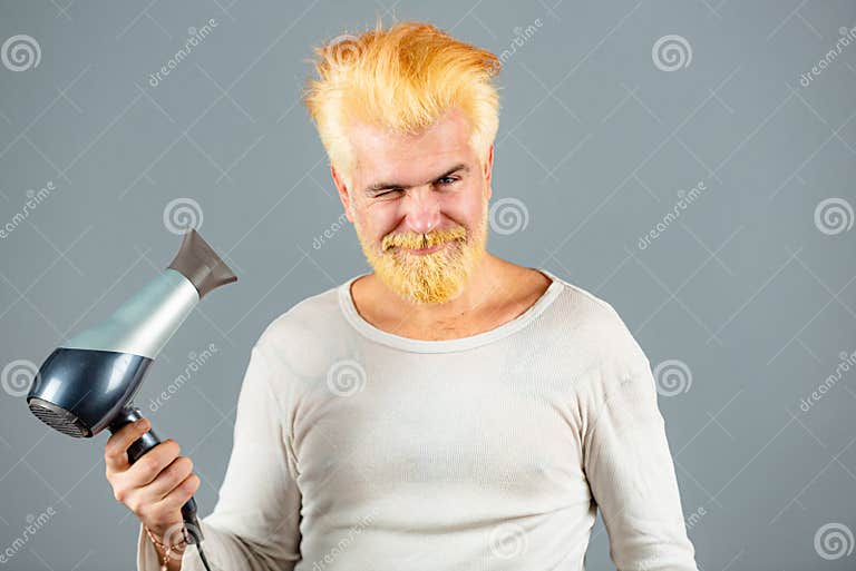 Handsome Redhead Man With Long Hair Dries His Hair With A Hairdryer
