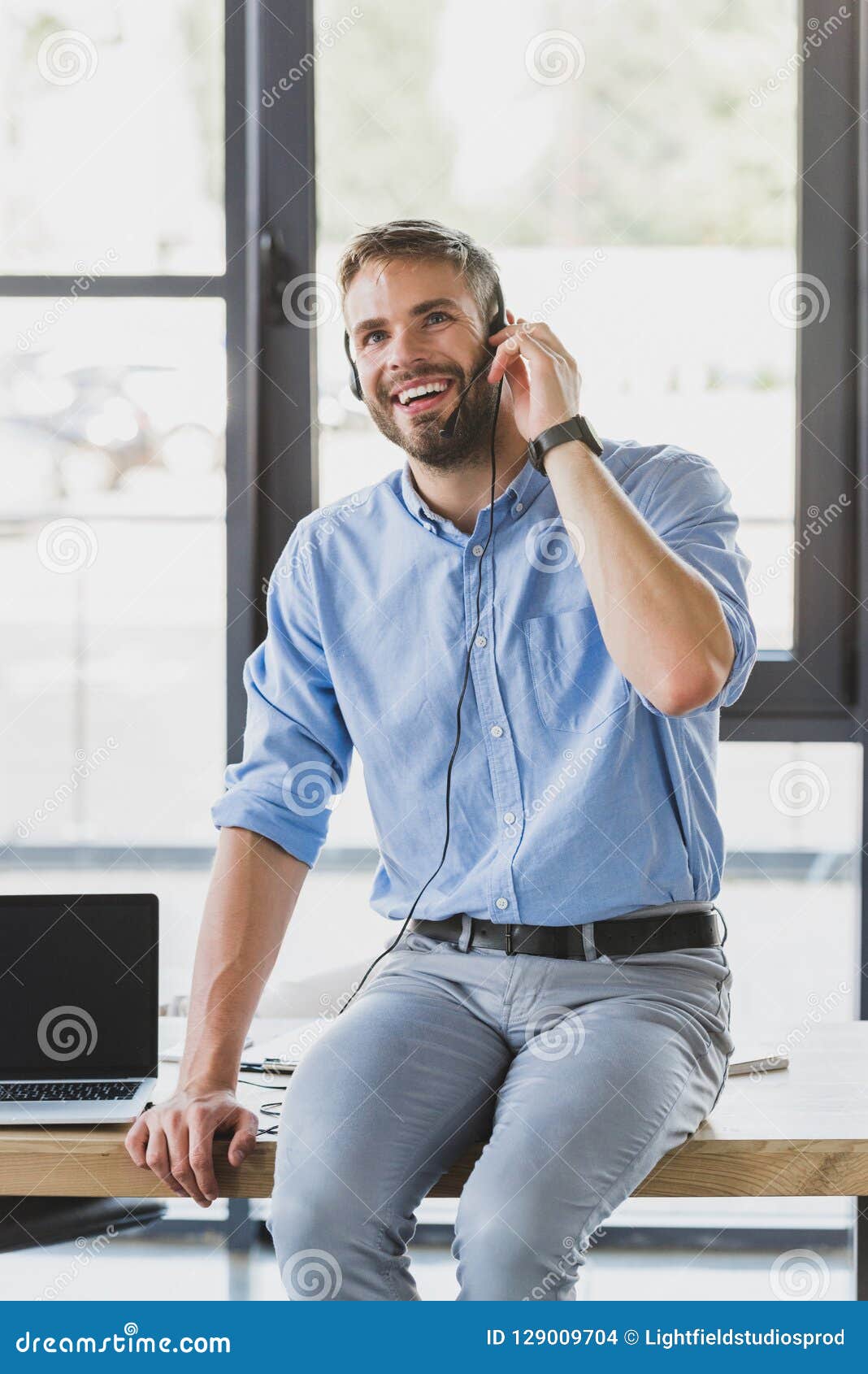 Handsome Smiling Young Call Center Operator in Headset Sitting on Table ...
