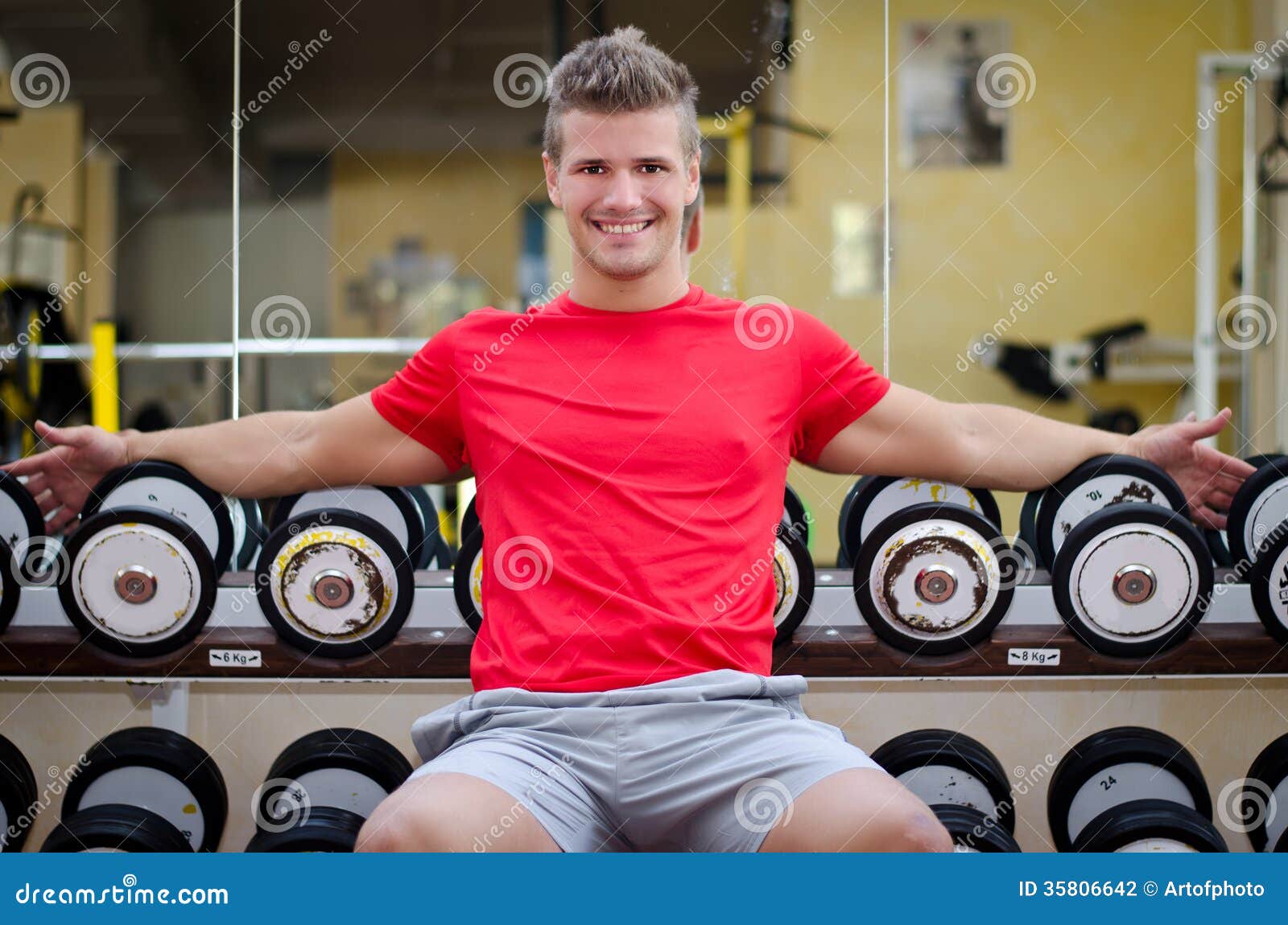 Handsome Smiling Young Man in Gym Sitting on Dumbbells Rack Stock Photo ...