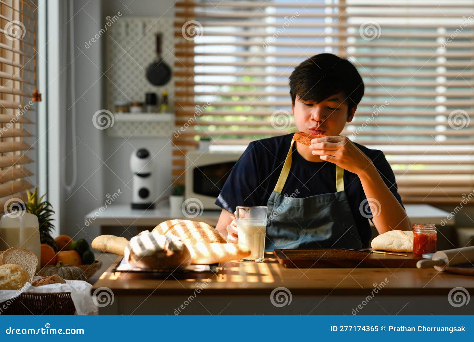 Handsome Young Asian Man Eating a Slice of Bread with Jam for Breakfast ...