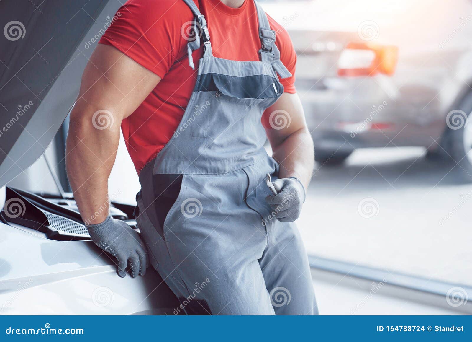 Handsome Young Auto Mechanic in Uniform is Examining Car in Auto ...