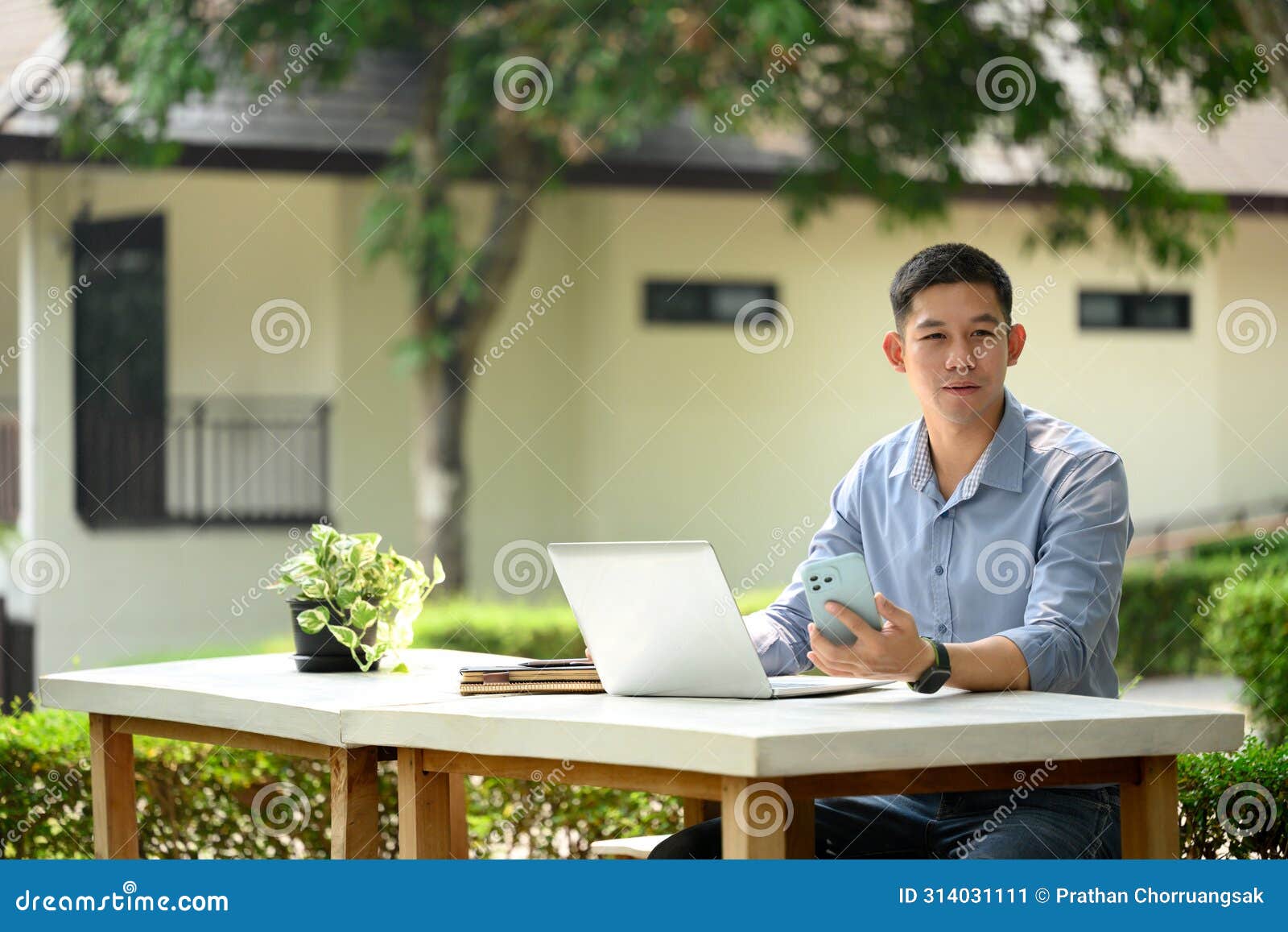 Handsome Young Businessman Using Laptop Outdoors, Holding Smartphone ...