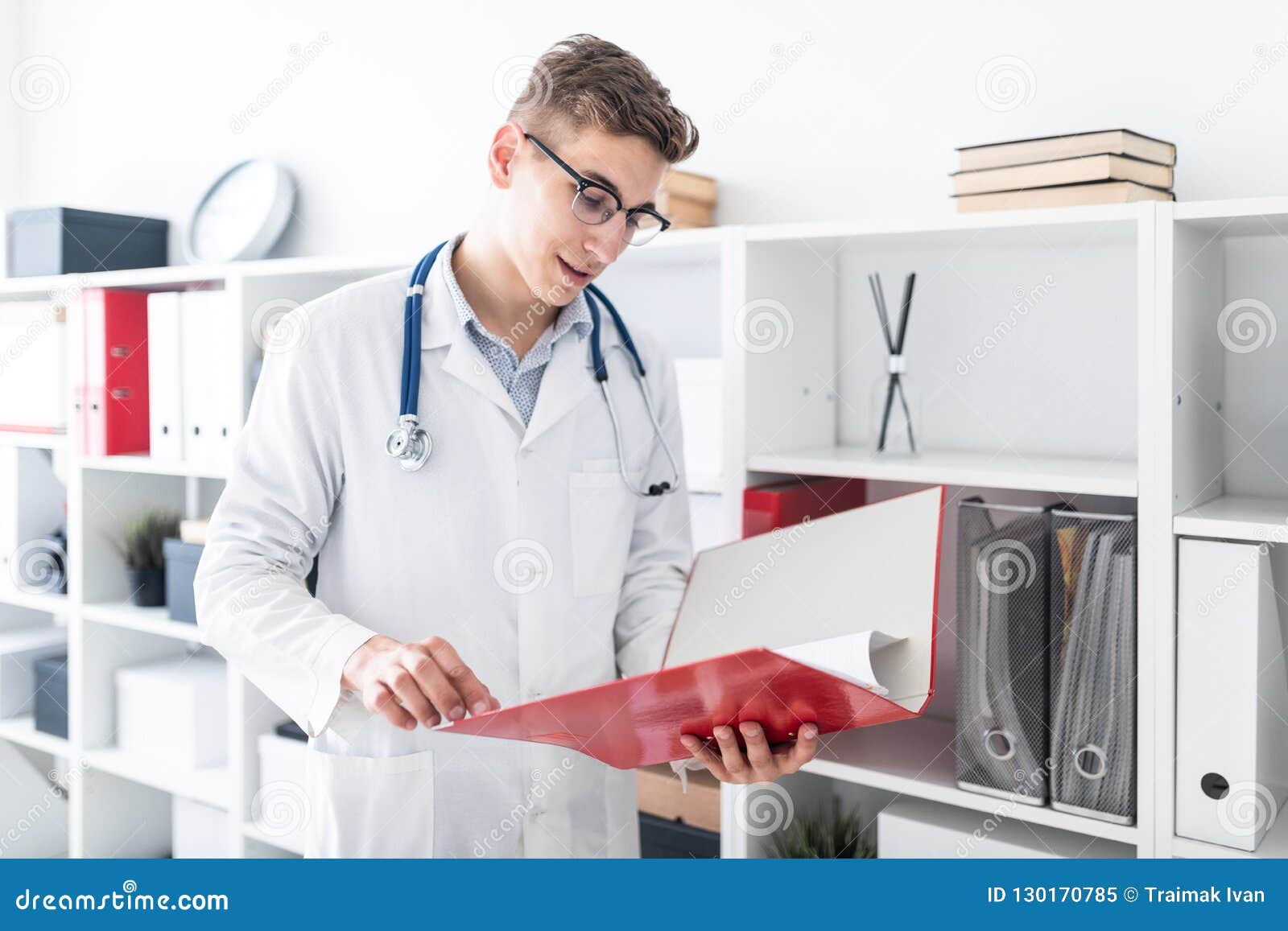 A Young Doctor in a White Robe Standing Near the Rack and Holding a ...