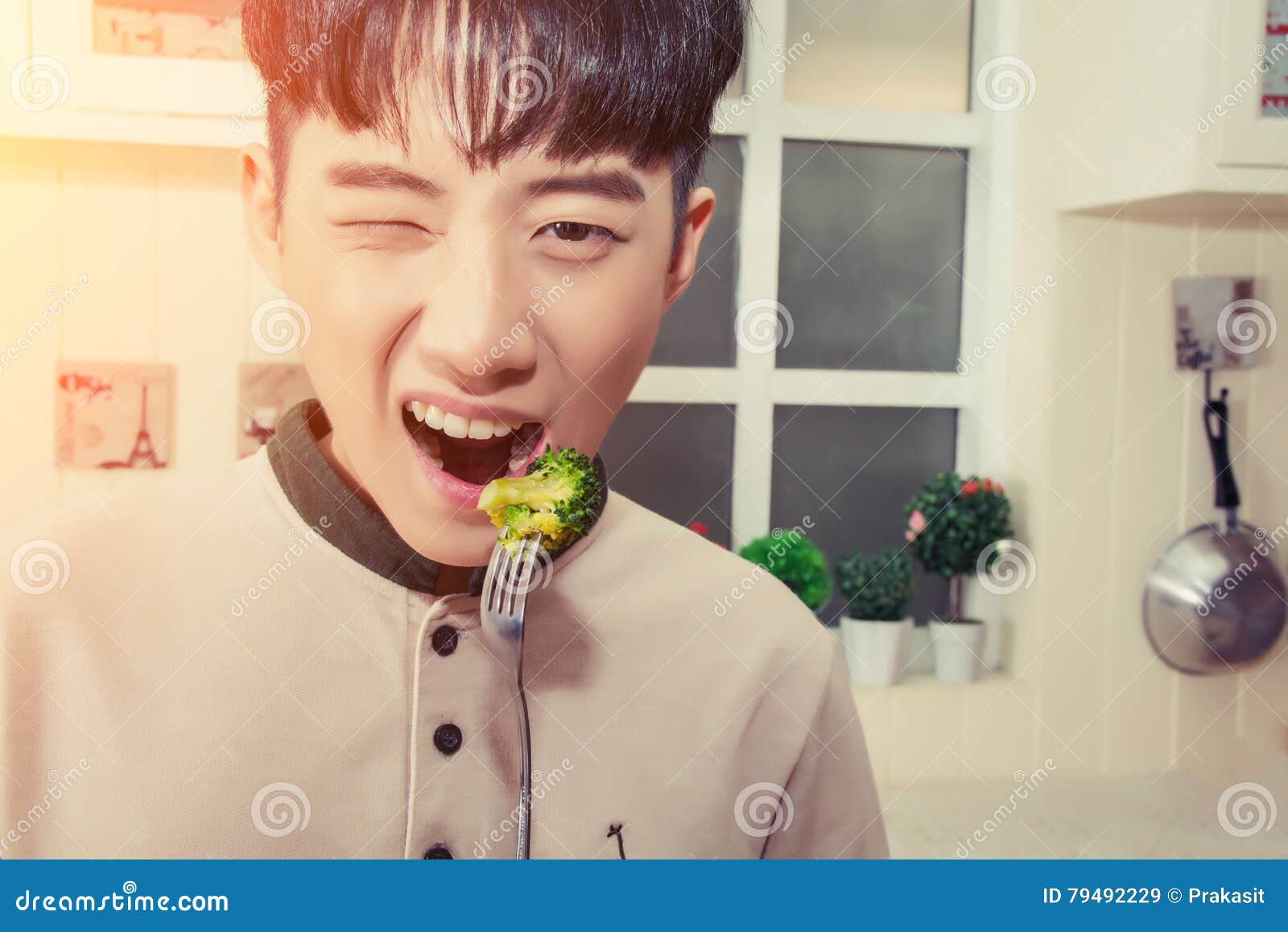 Handsome Young Man Eating Broccoli in the Kitchen Smiley with Cl Stock ...
