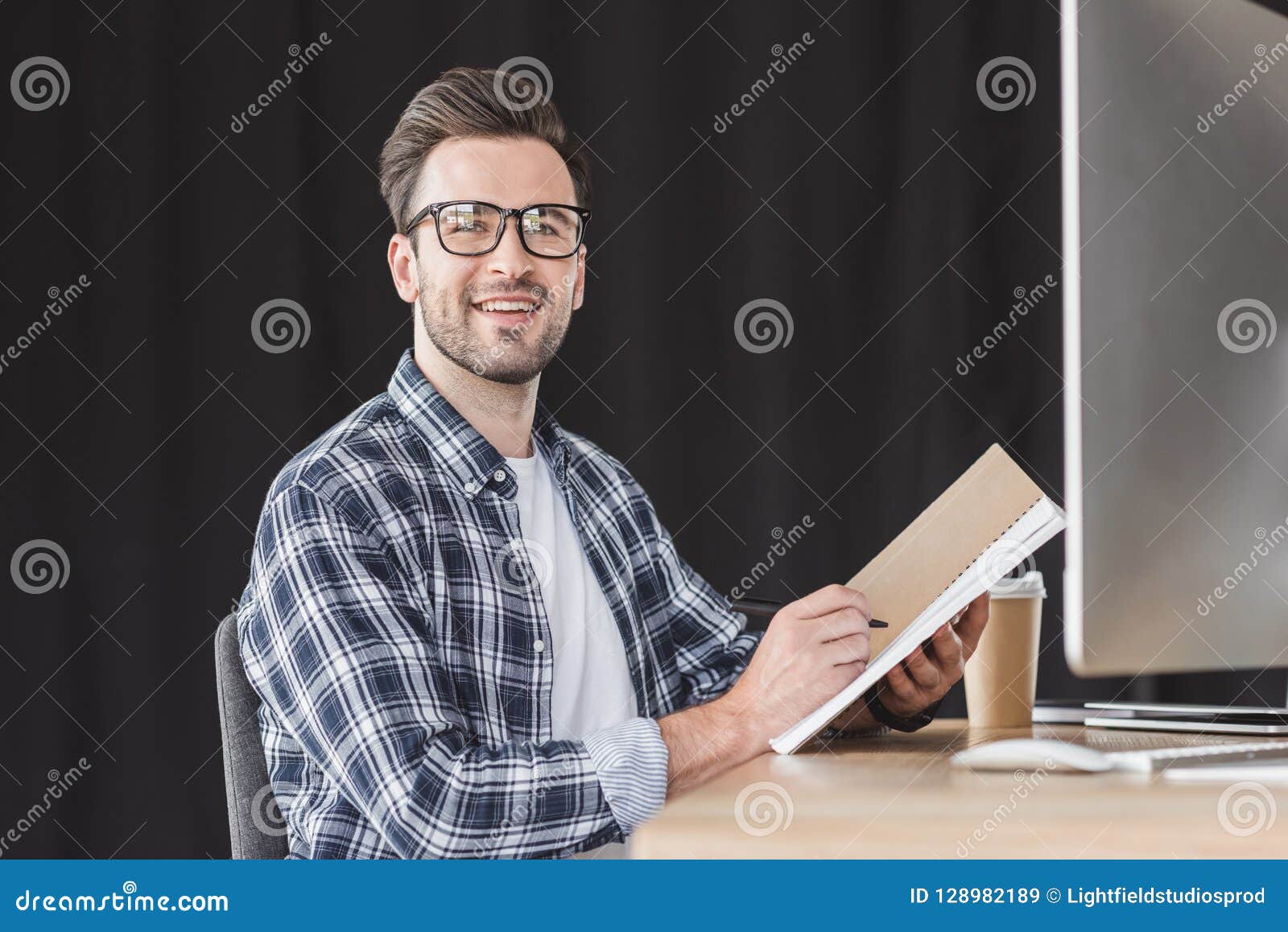 Handsome Young Man in Eyeglasses Taking Notes in Notebook and Smiling ...
