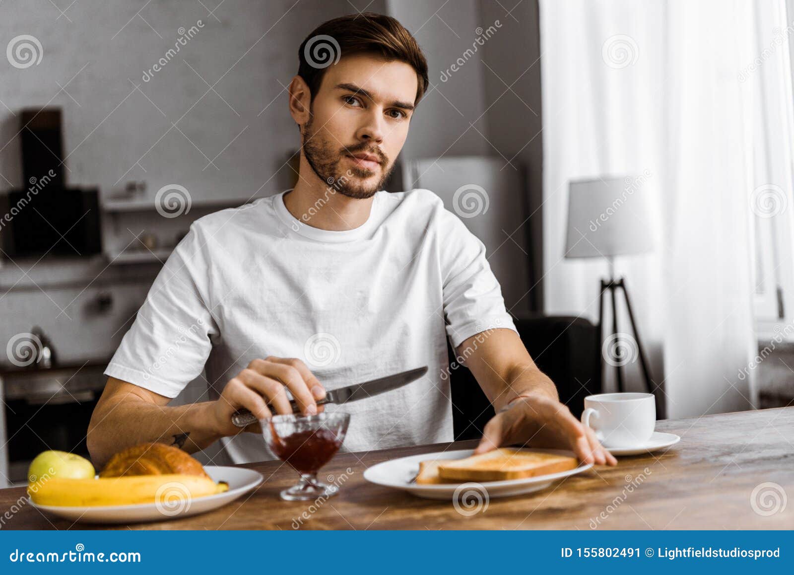 Handsome Young Man Having Toasts with Jam and Fruits for Breakfast and ...