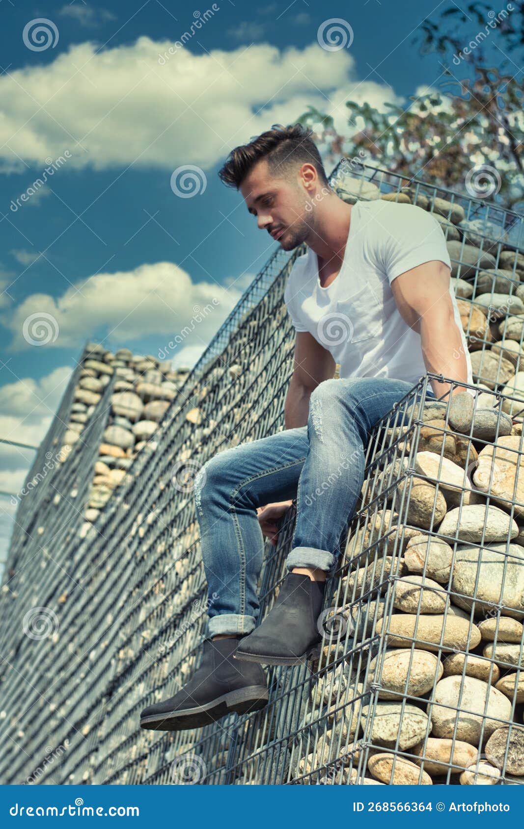 Handsome Young Man Sitting on Stone Blocks Stock Photo - Image of ...