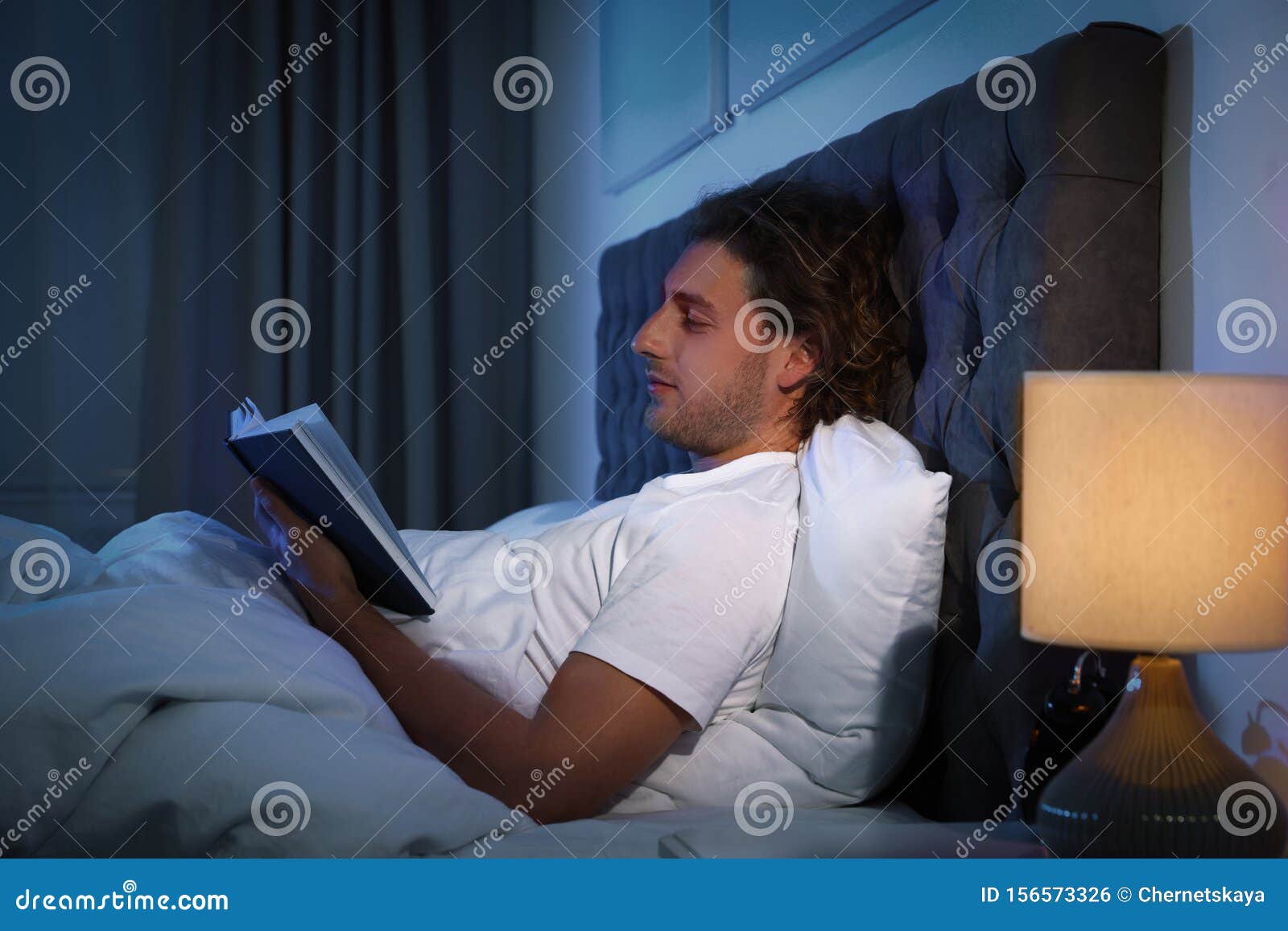 Handsome Young Man Reading Book in Dark Room at Night Stock Photo ...