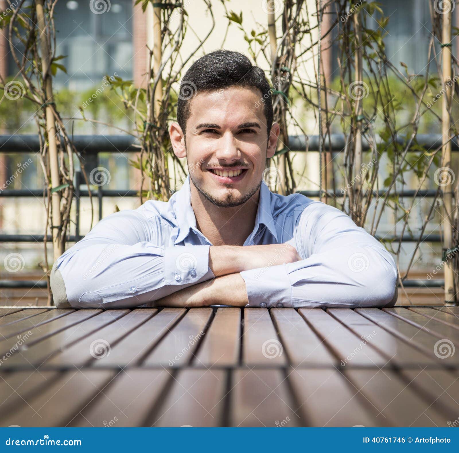Handsome Young Man Resting Crossed Arms on Wood Surface Stock Photo ...