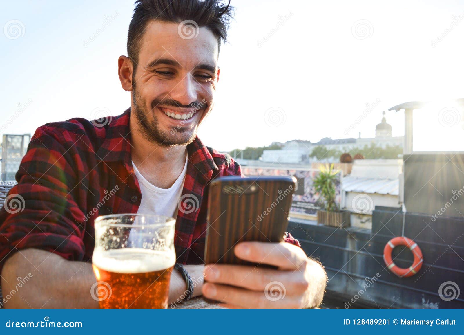 Handsome Young Man Smiling Looking at the Phone and Drinking a Beer in ...