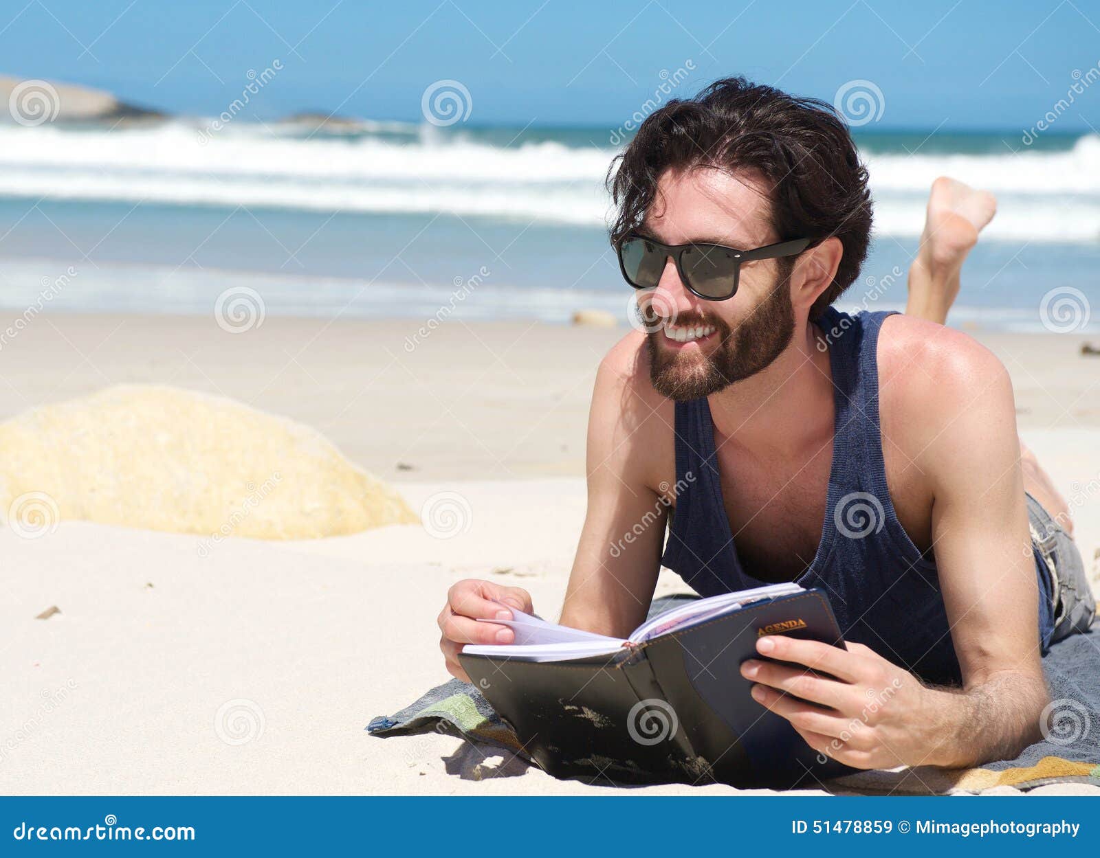 Handsome Young Man Smiling and Reading Book on the Beach Stock Image ...